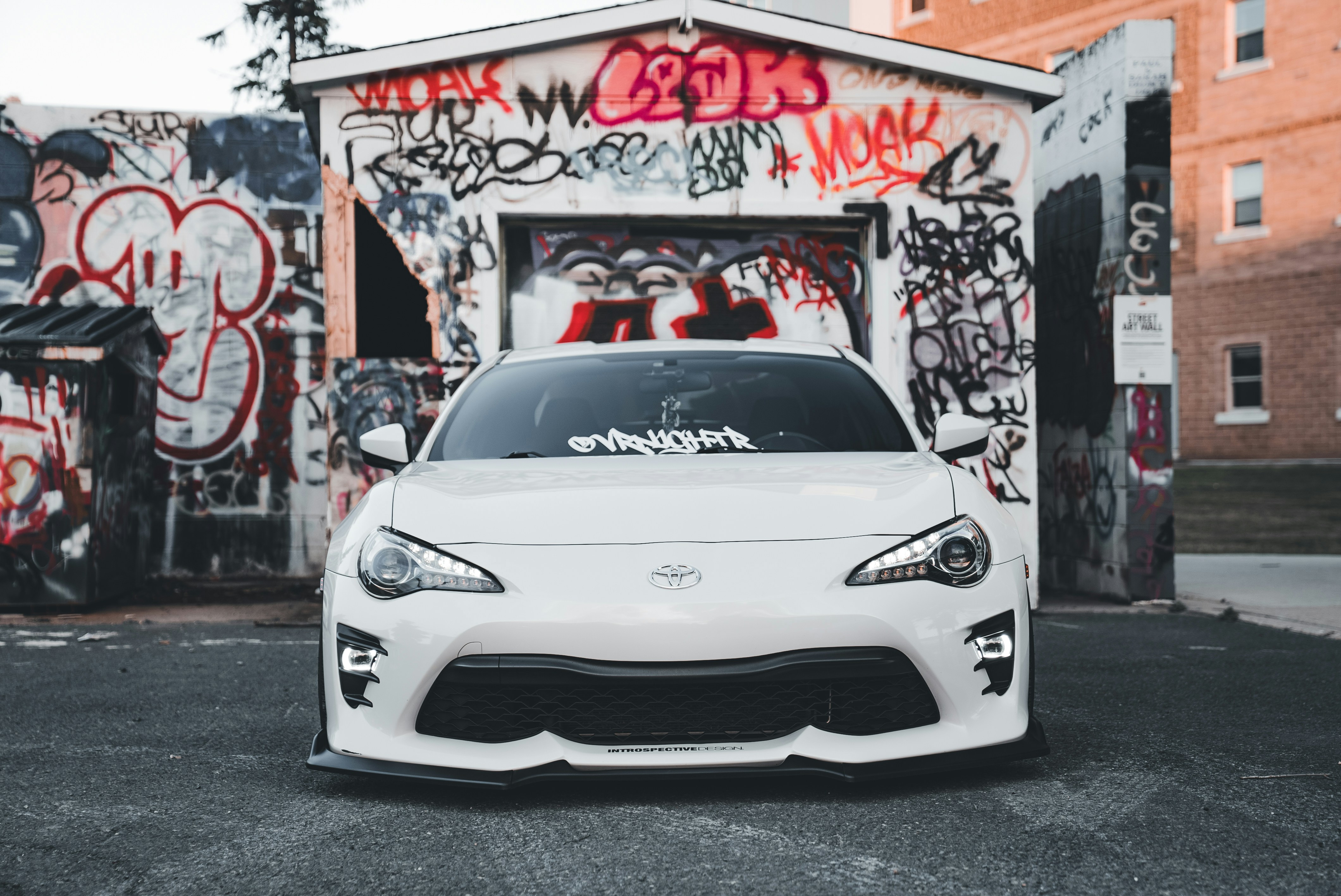 White Sport Sedan Anchored by a Graffiti Corridor