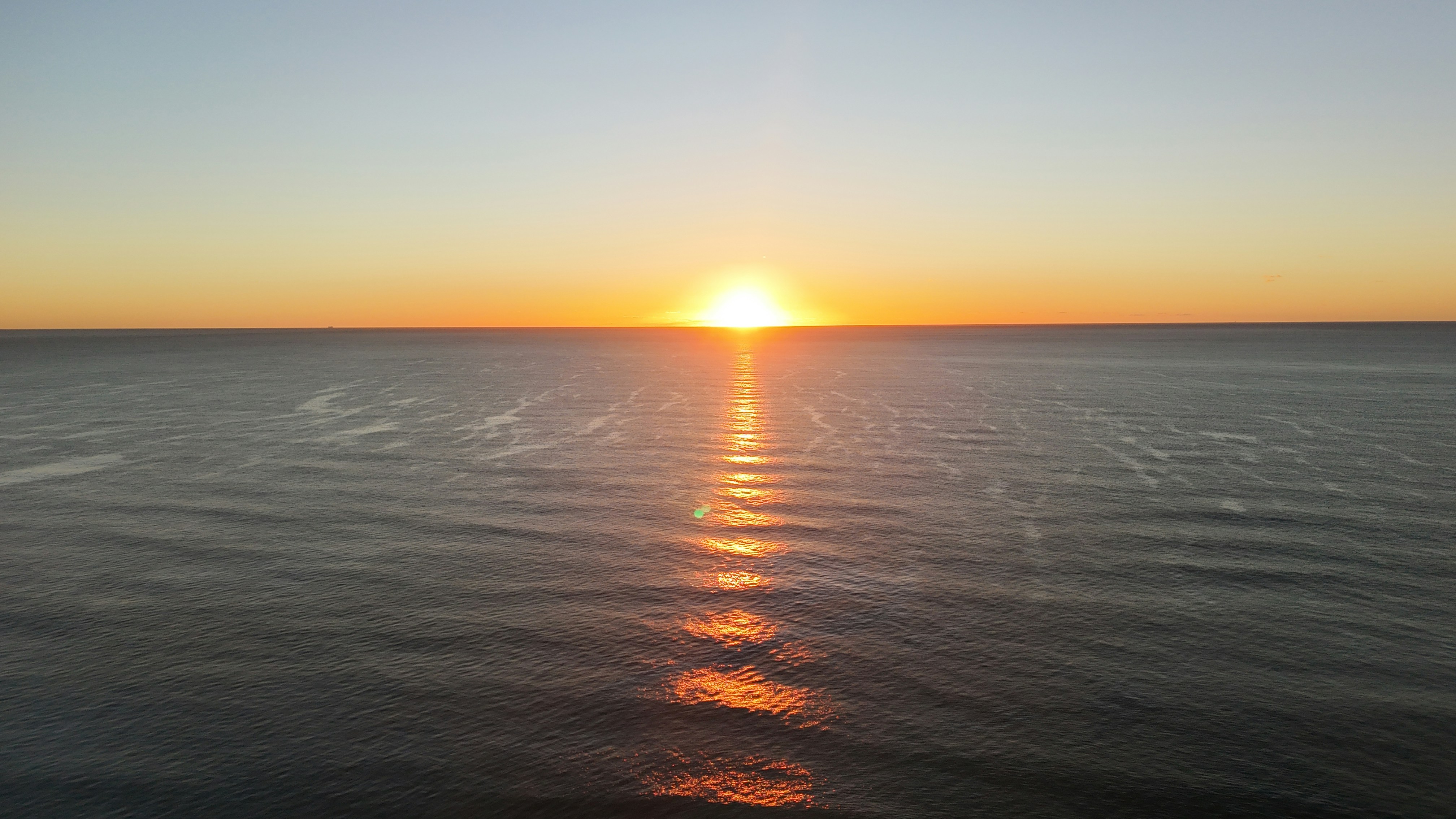 The sun sets over the vast and tranquil ocean.