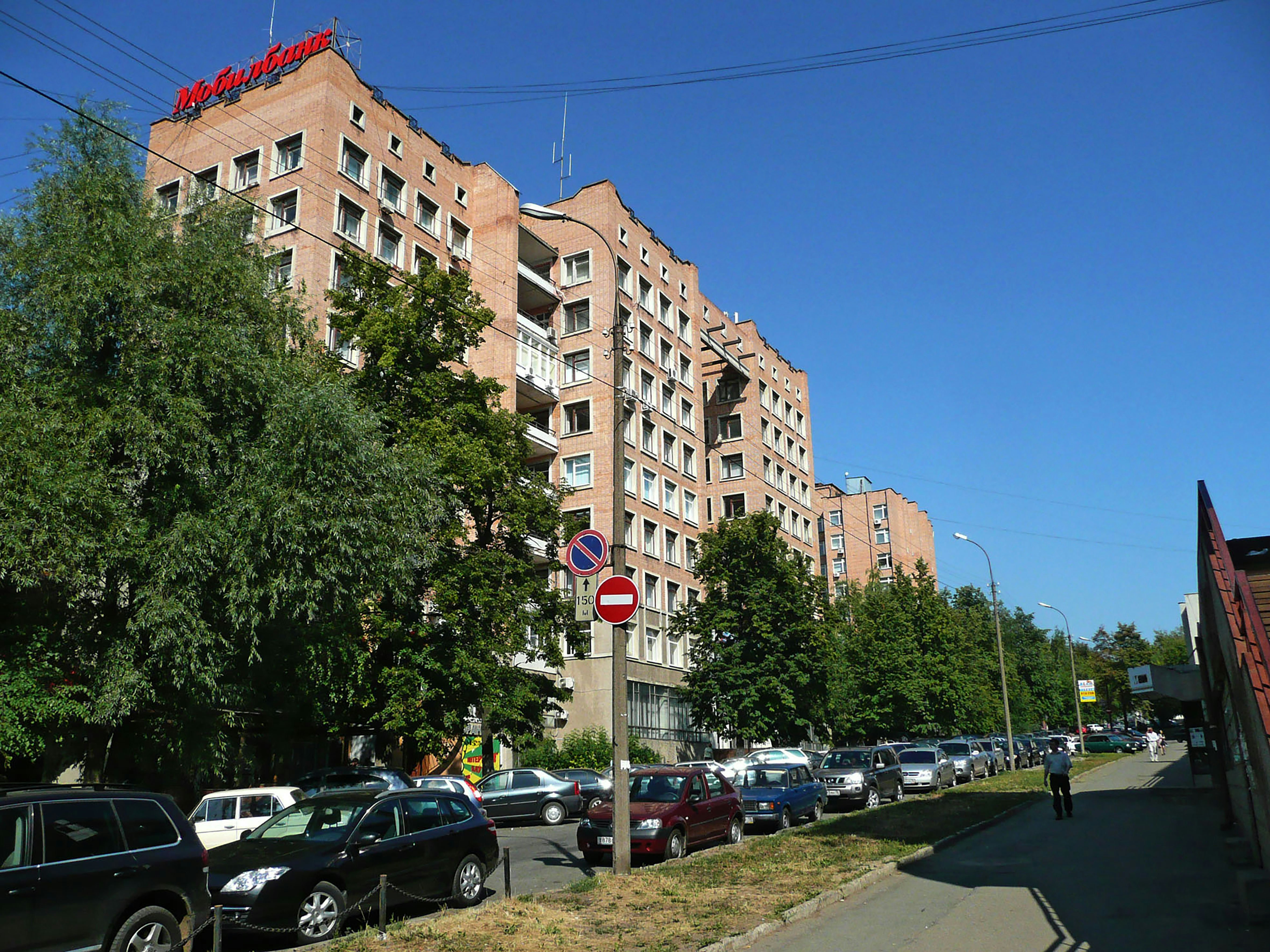 izhevsk august 2009 | A large brick building sits on a sunny street.