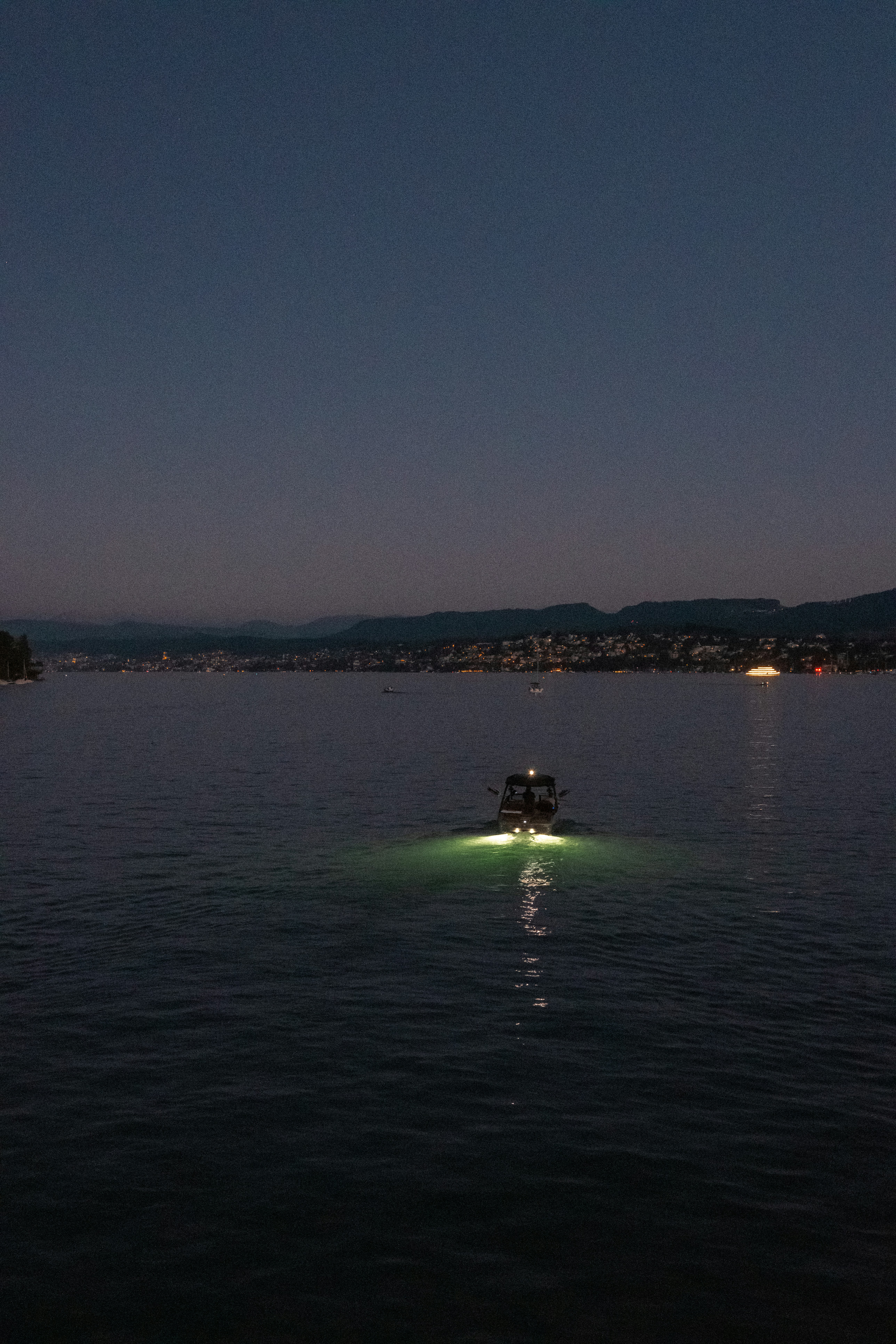 Midnight Beacon: Boat's Green Wake Casting a Gate Across the Quiet Sea