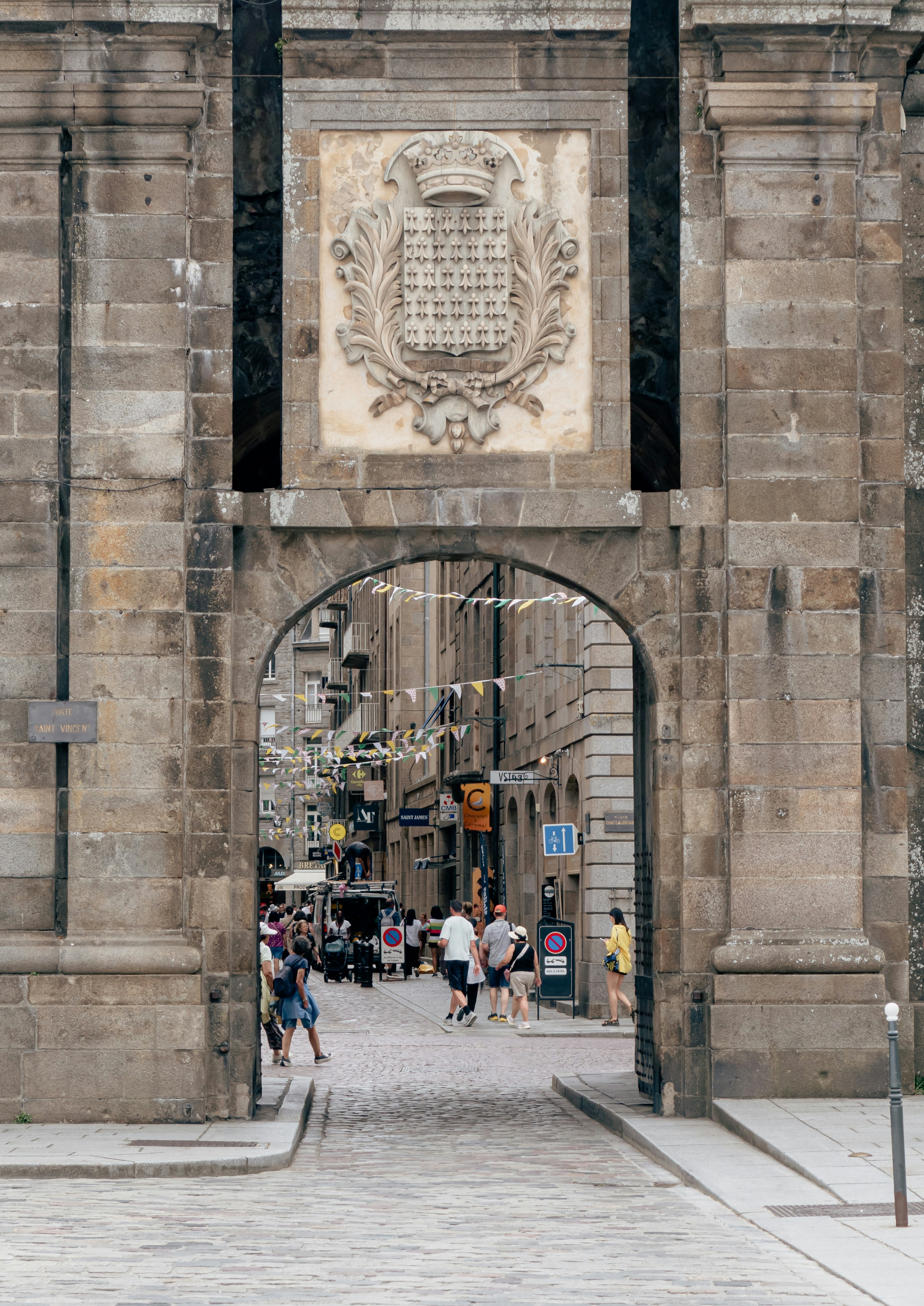 A stone archway leads to a busy street.