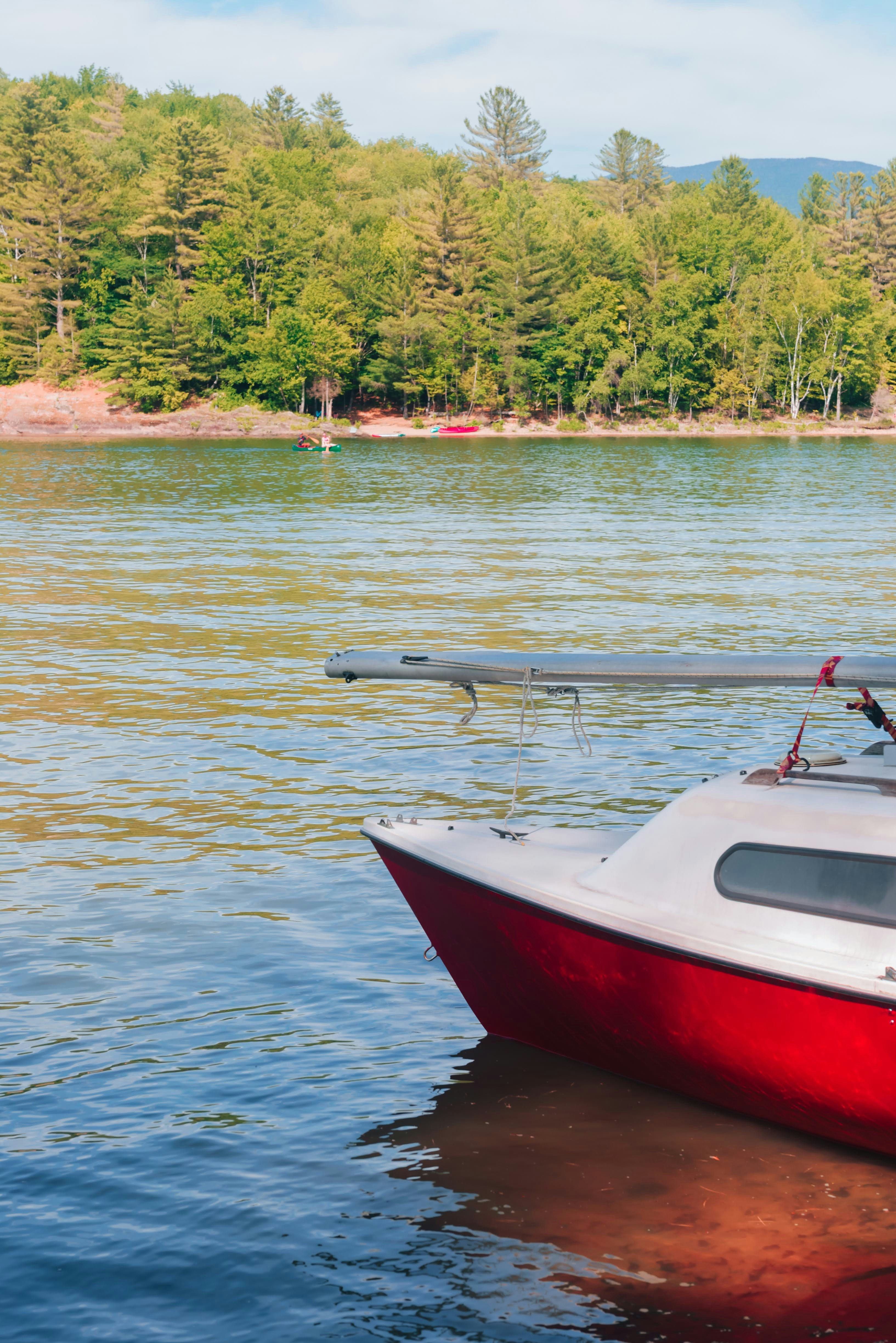 A red boat floats on a peaceful lake.