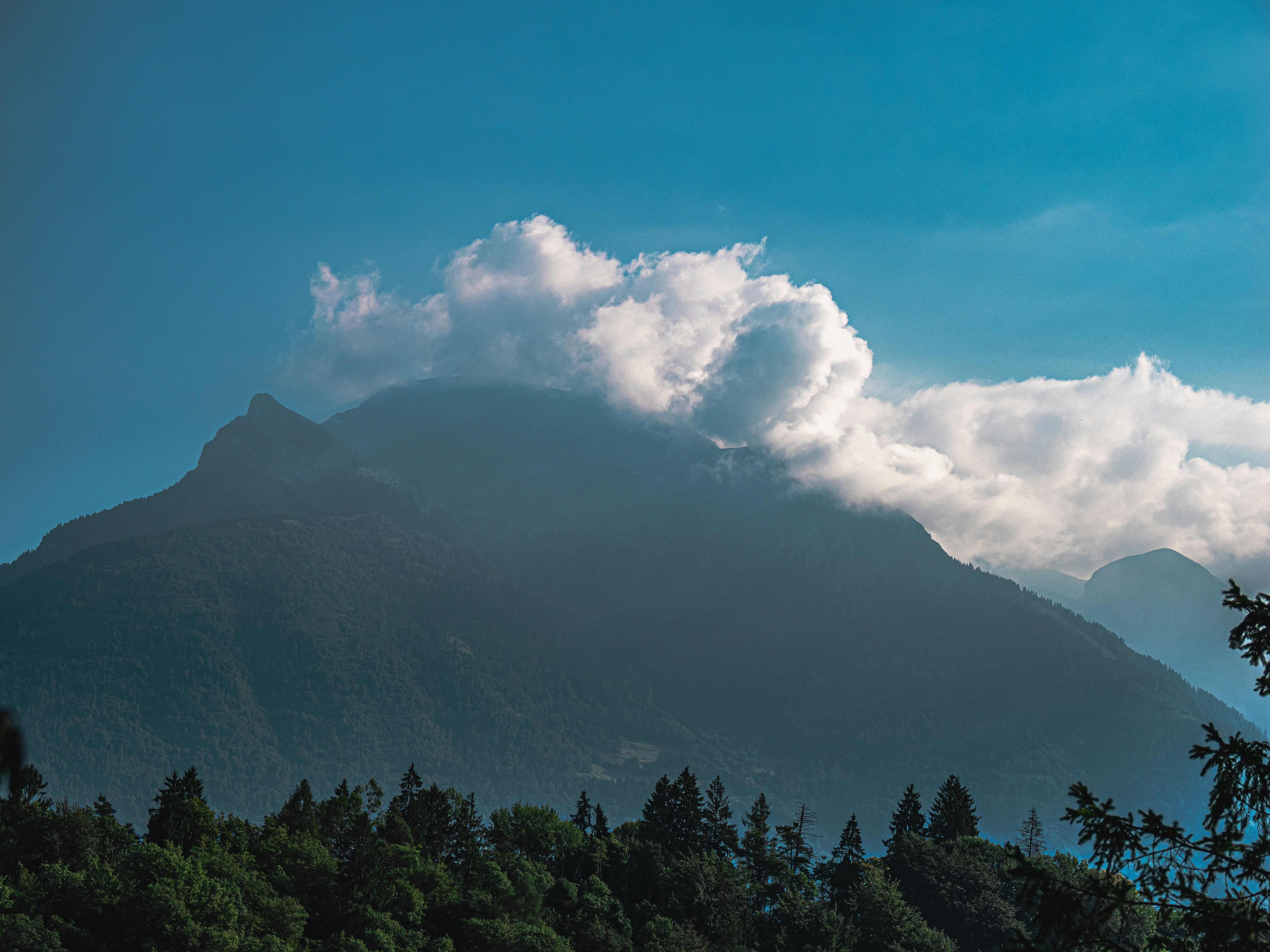 A mountain is shrouded by clouds in a blue sky.
