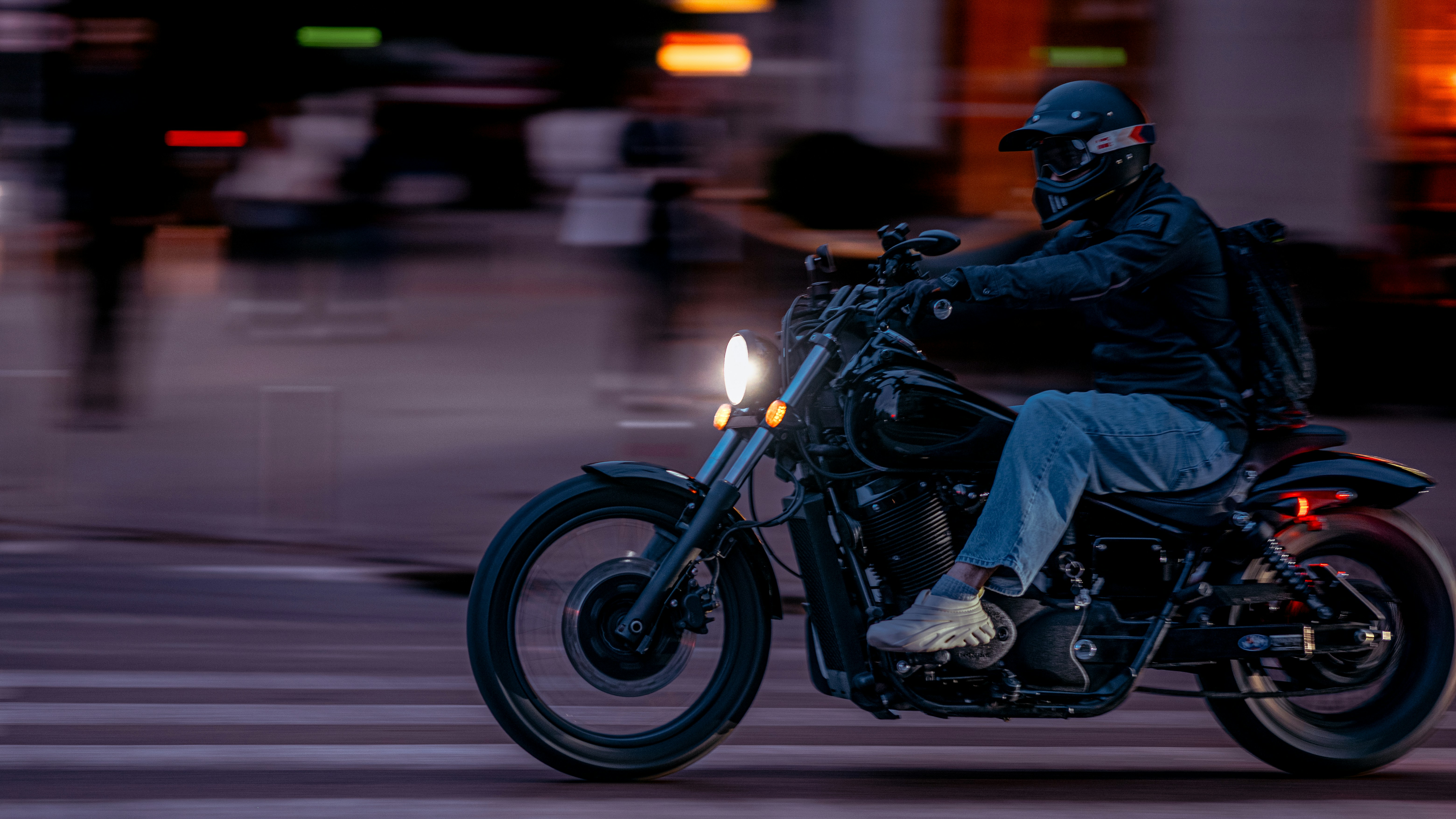 A motorcyclist rides along a city street at night.