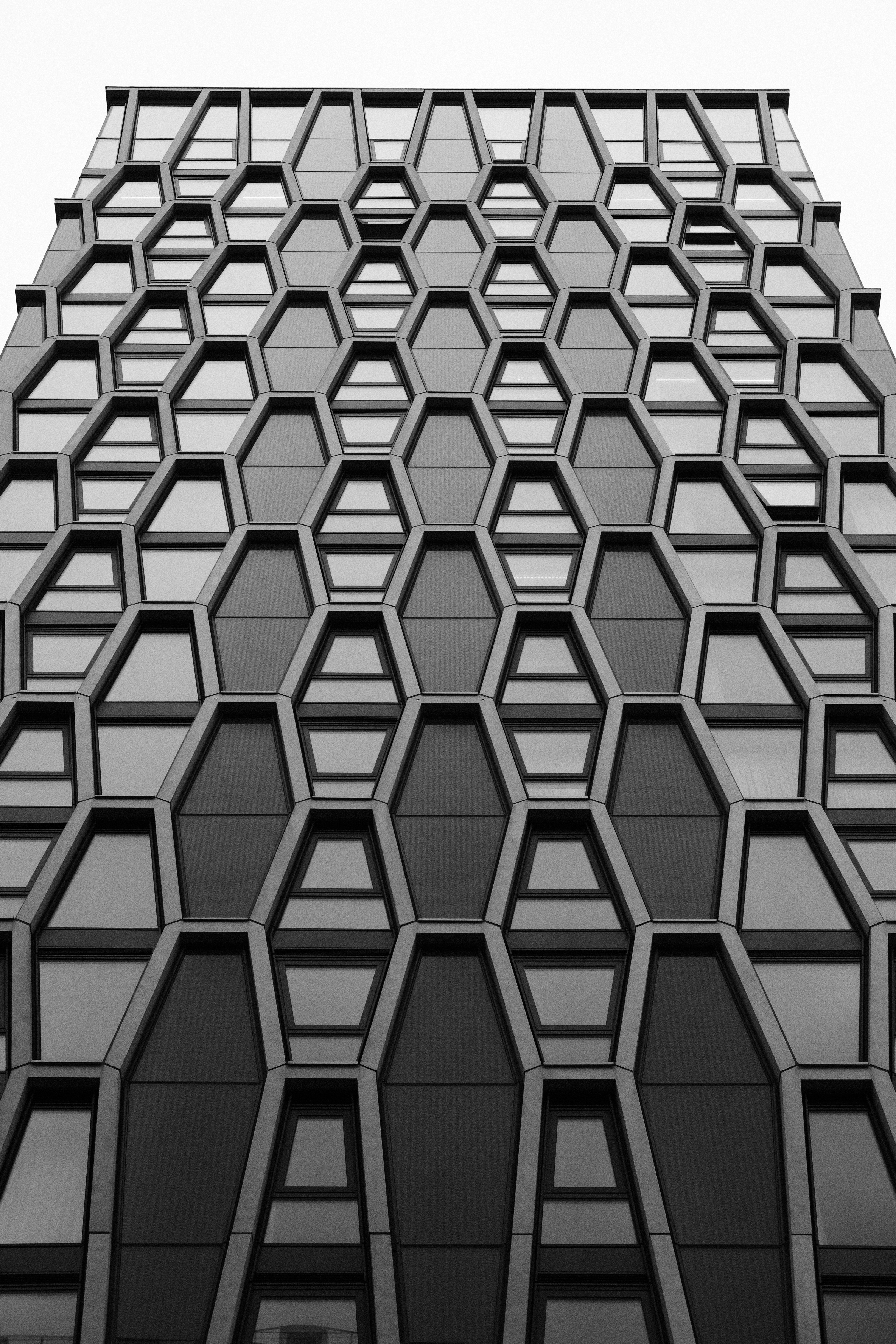 Hexagonal patterns dominate the facade of a contemporary building, showcasing a striking interplay of light and shadow.
