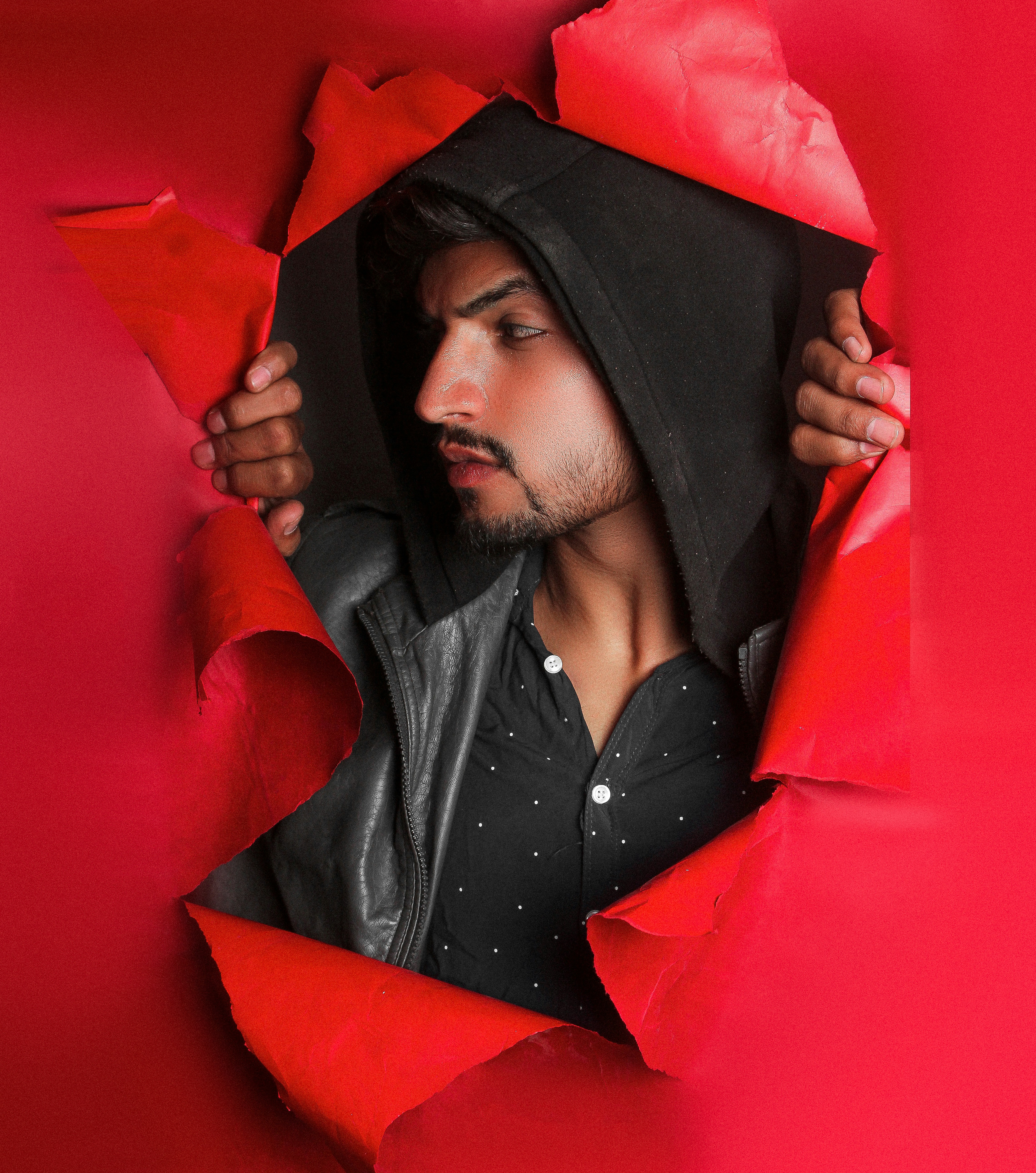 Crimson Frame: Hooded Gaze Through Torn Red Veils