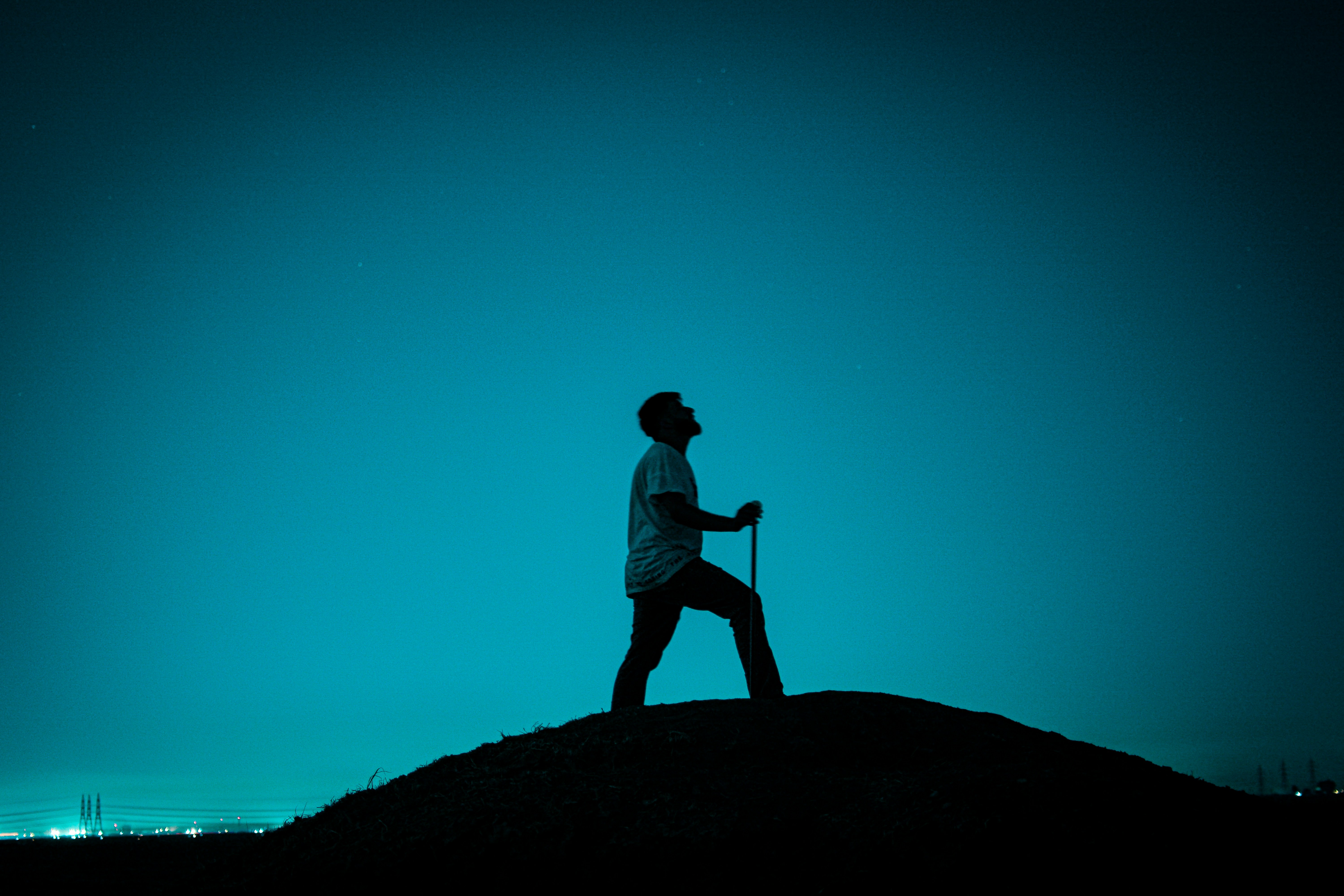 A person climbs a hill under a blue sky.