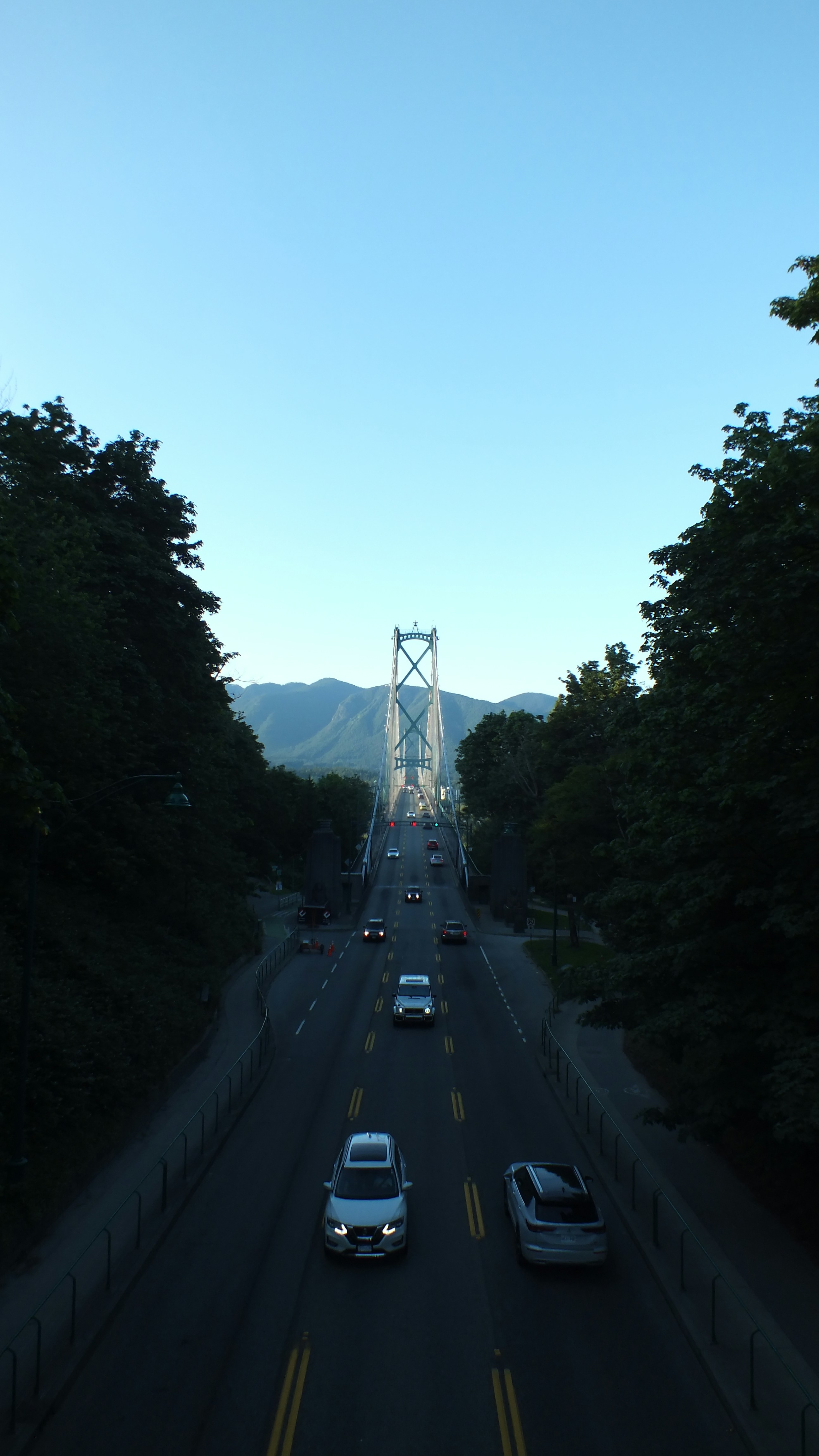 Cars drive on a road towards a bridge.