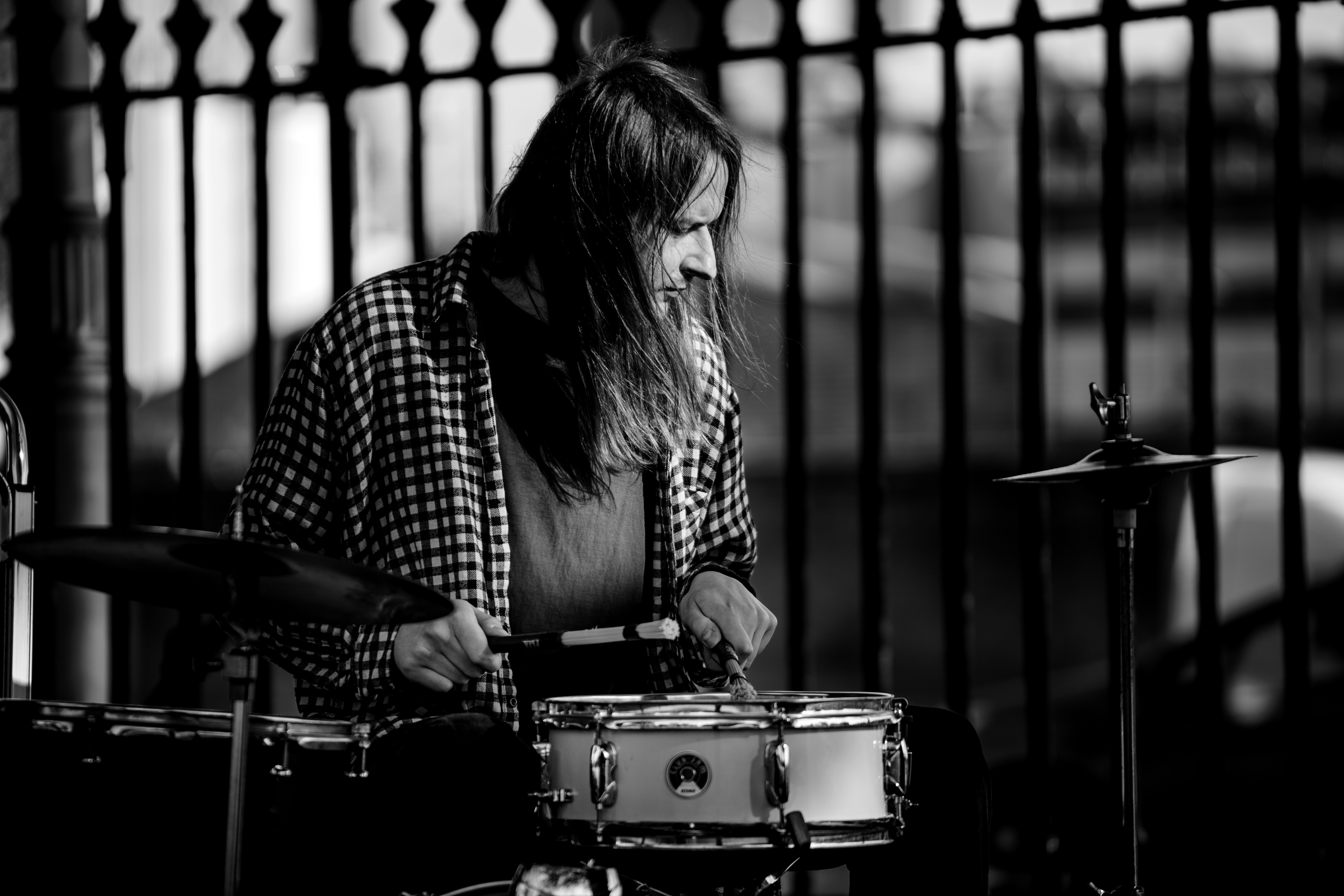 A musician plays drums in black and white.