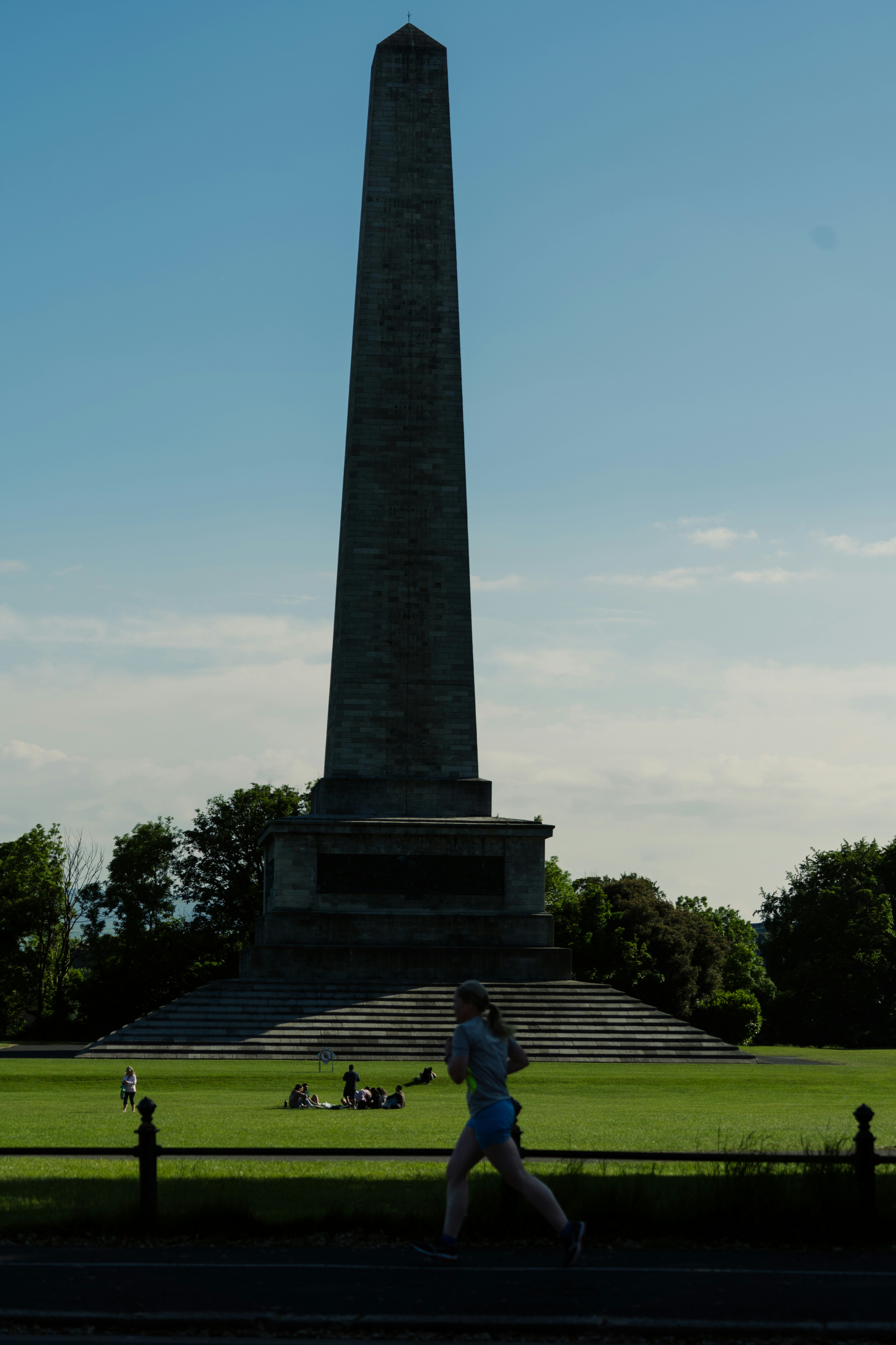 A runner is silhouetted near a tall monument.