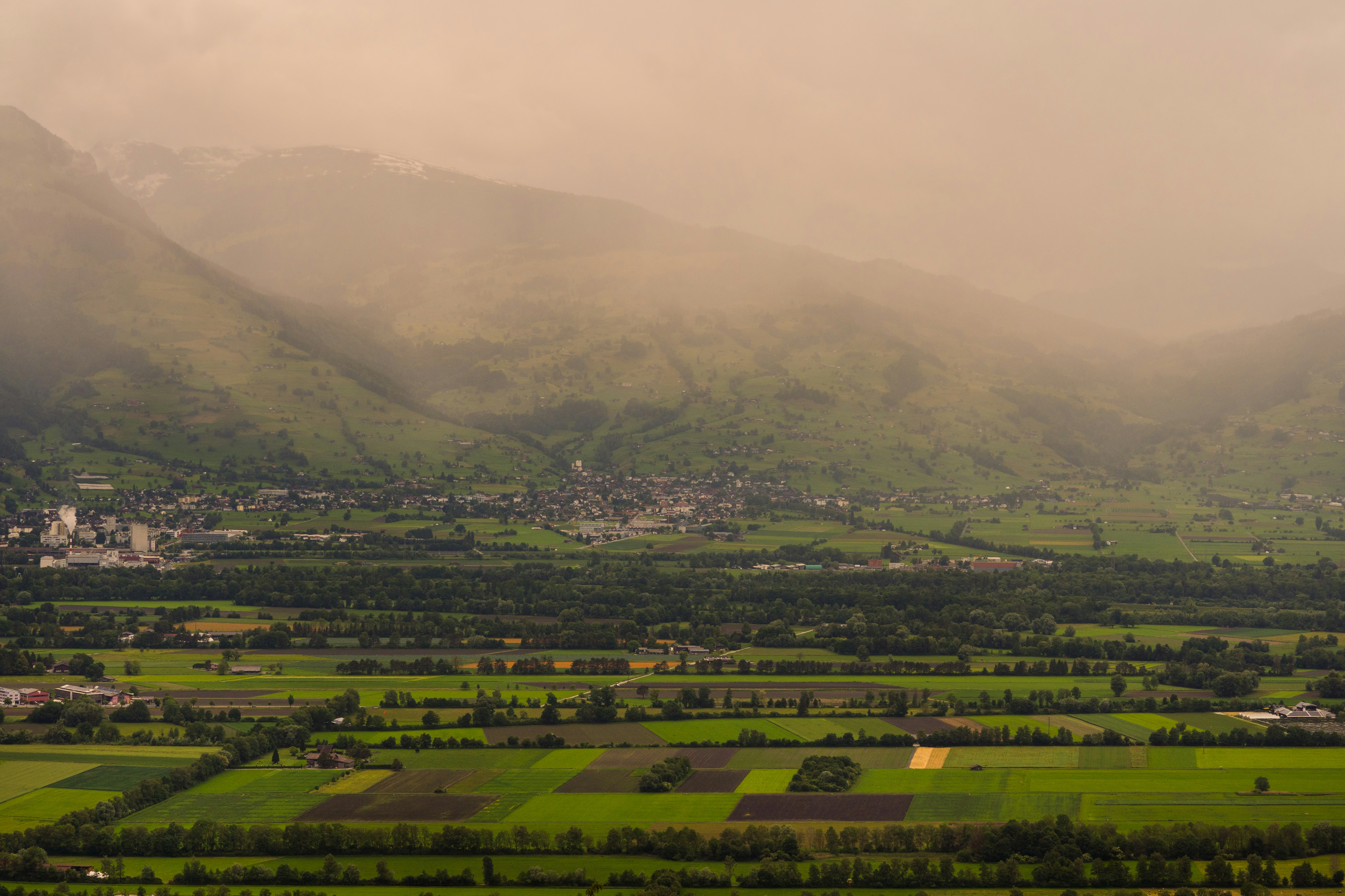 Fields and a town are set against mountains.