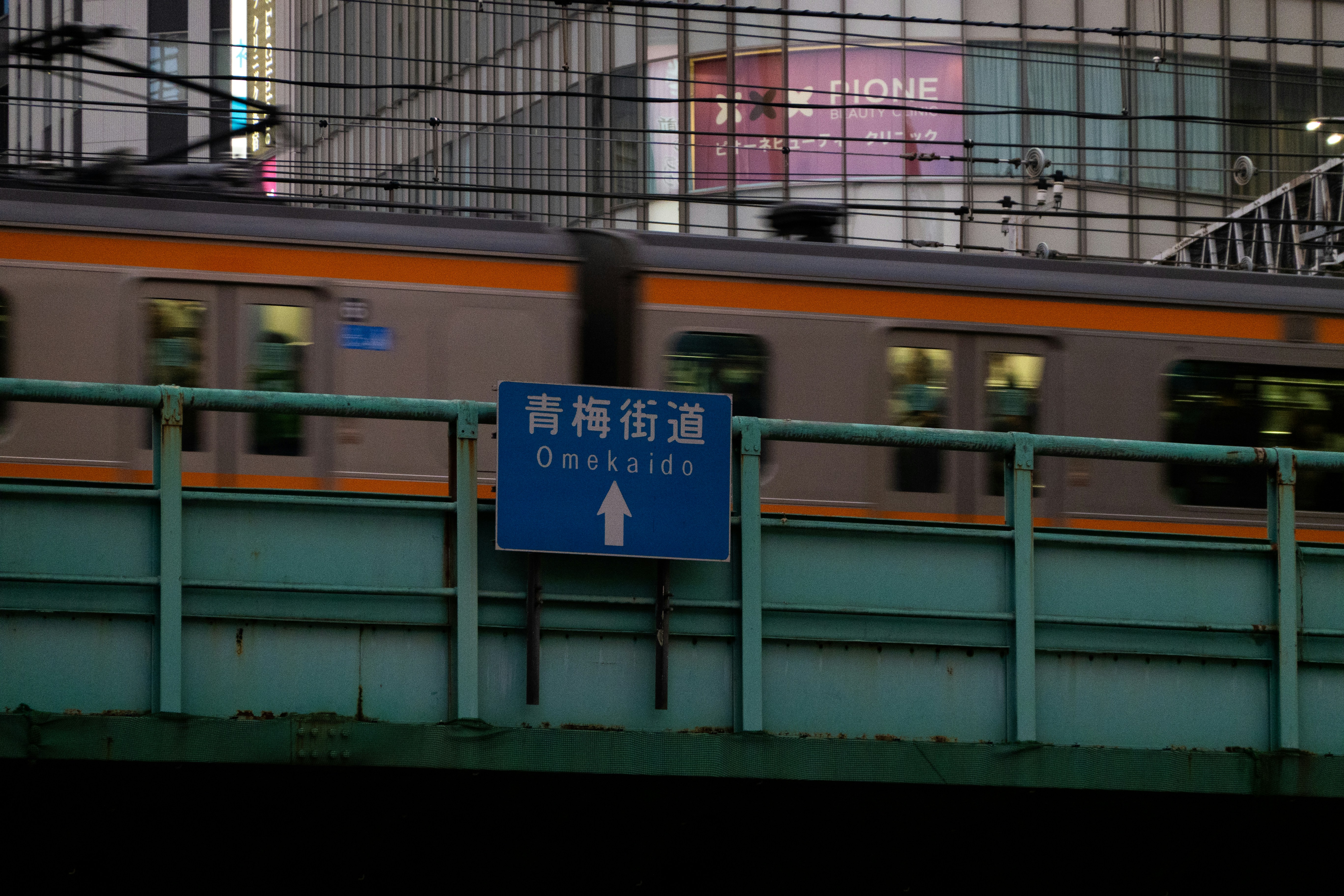 Tokyo 2025 | A train speeds past a street sign.