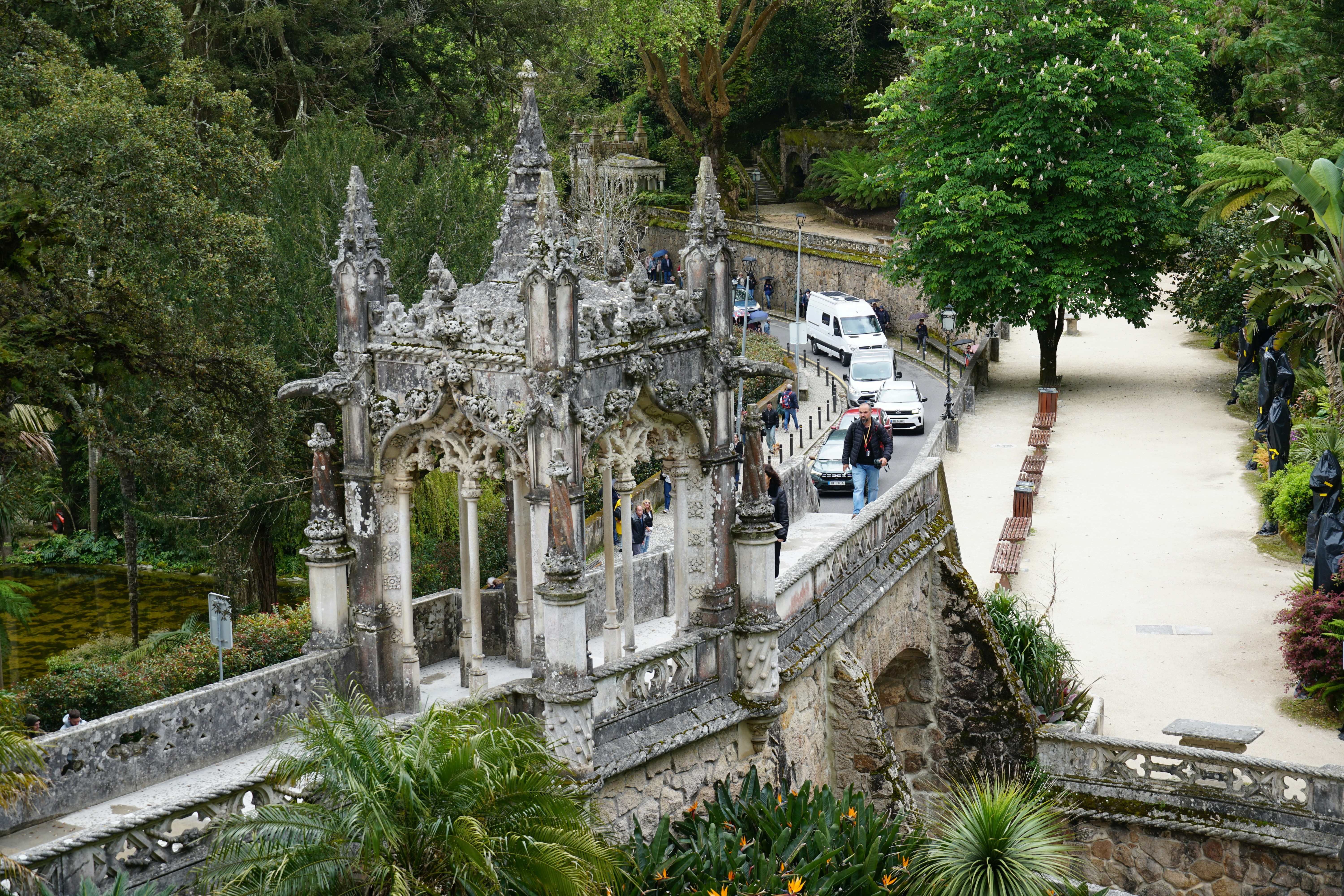 An ornate stone bridge winds through lush greenery.
