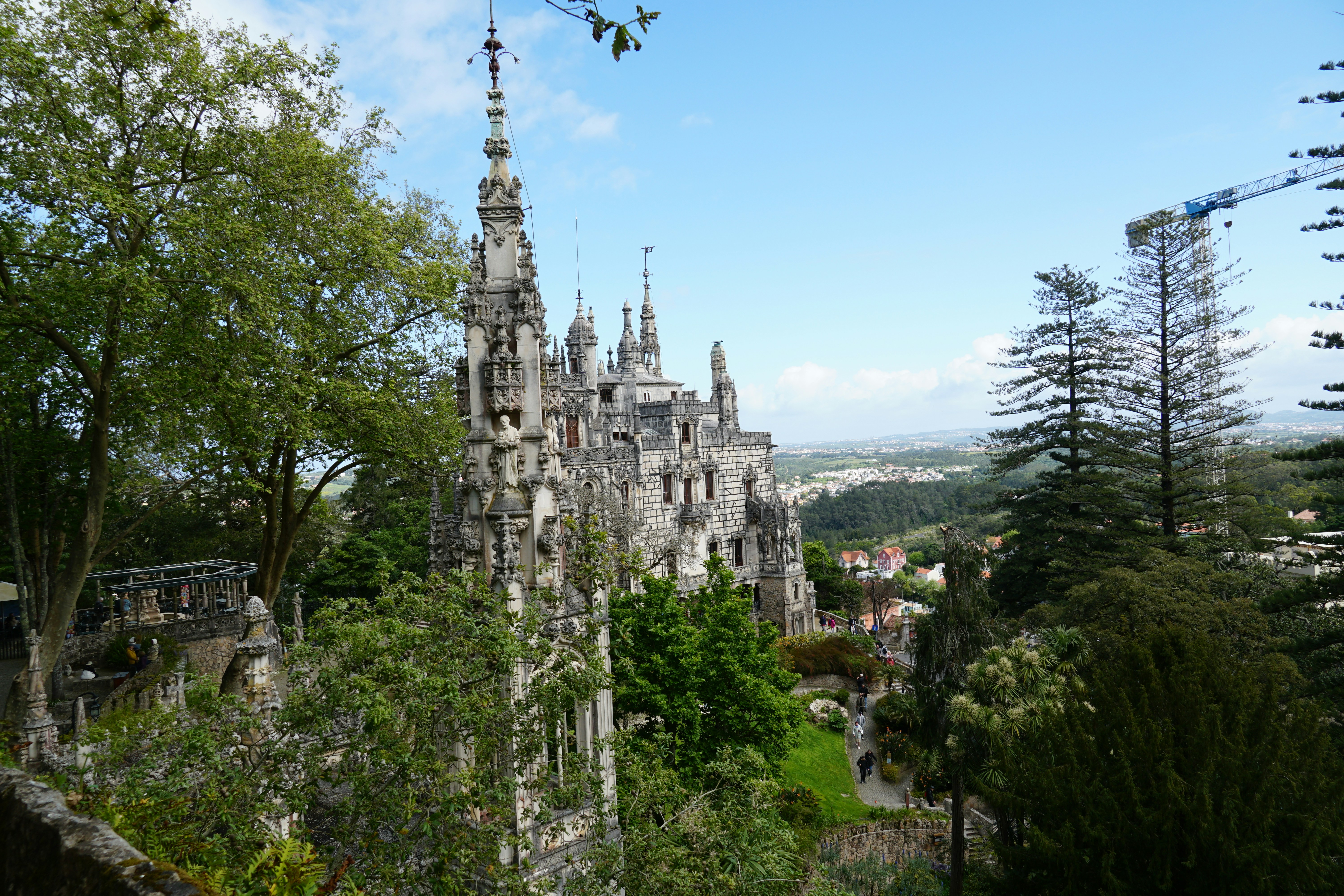 Intricately designed castle nestled among lush greenery, overlooking a sprawling landscape under a clear blue sky.