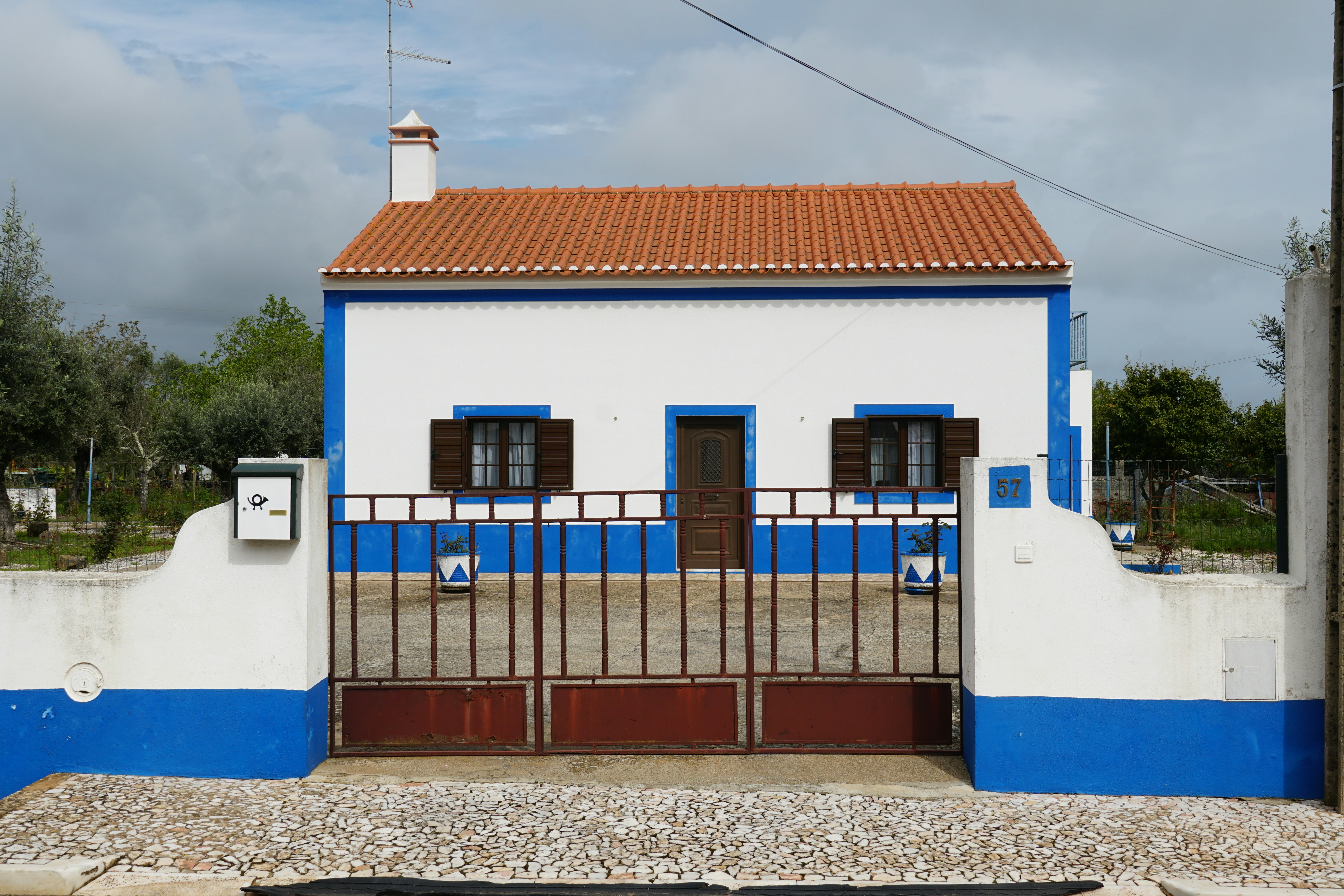 Azure-Trimmed Cottage Framed by a Rust-Red Gate