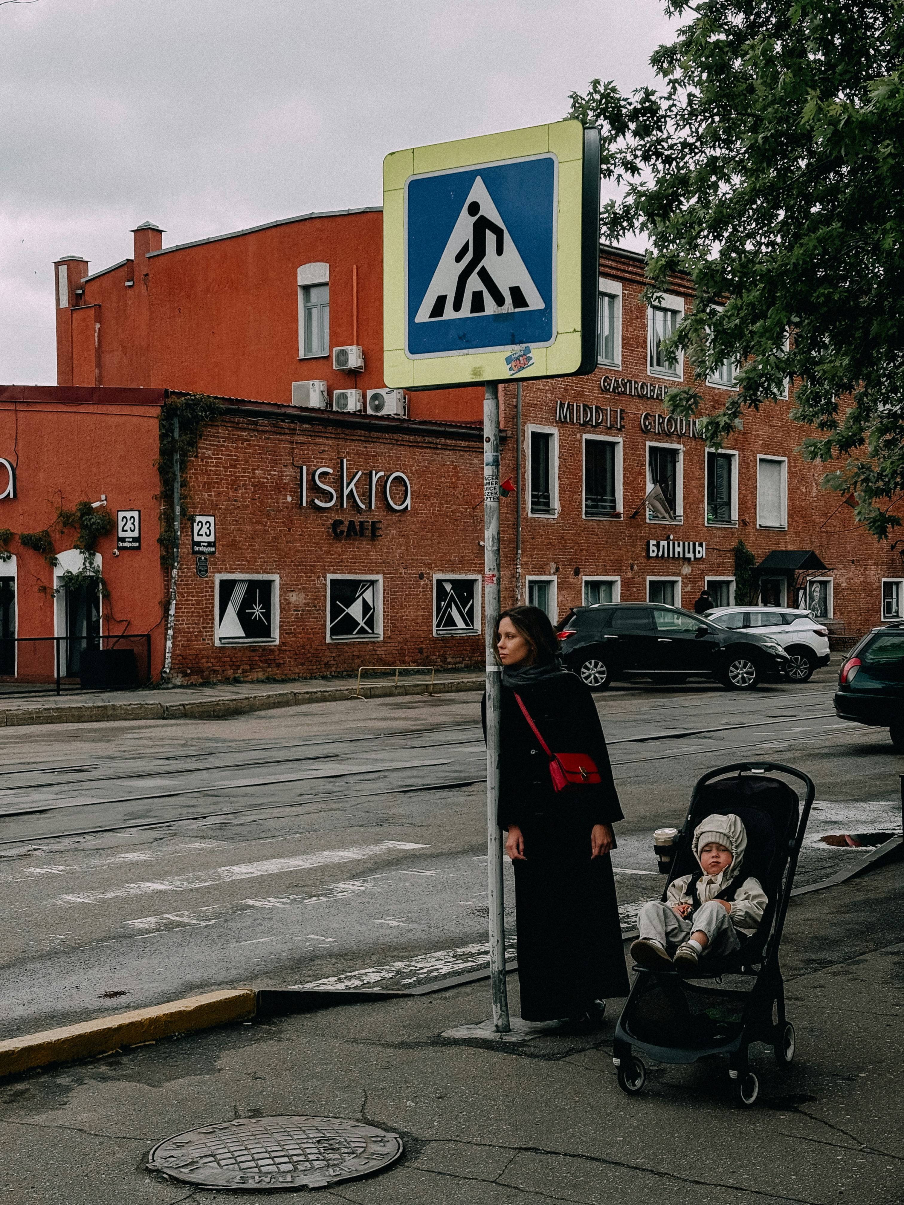 Crosswalk Quiet: A Mother and Stroller at a City Corner