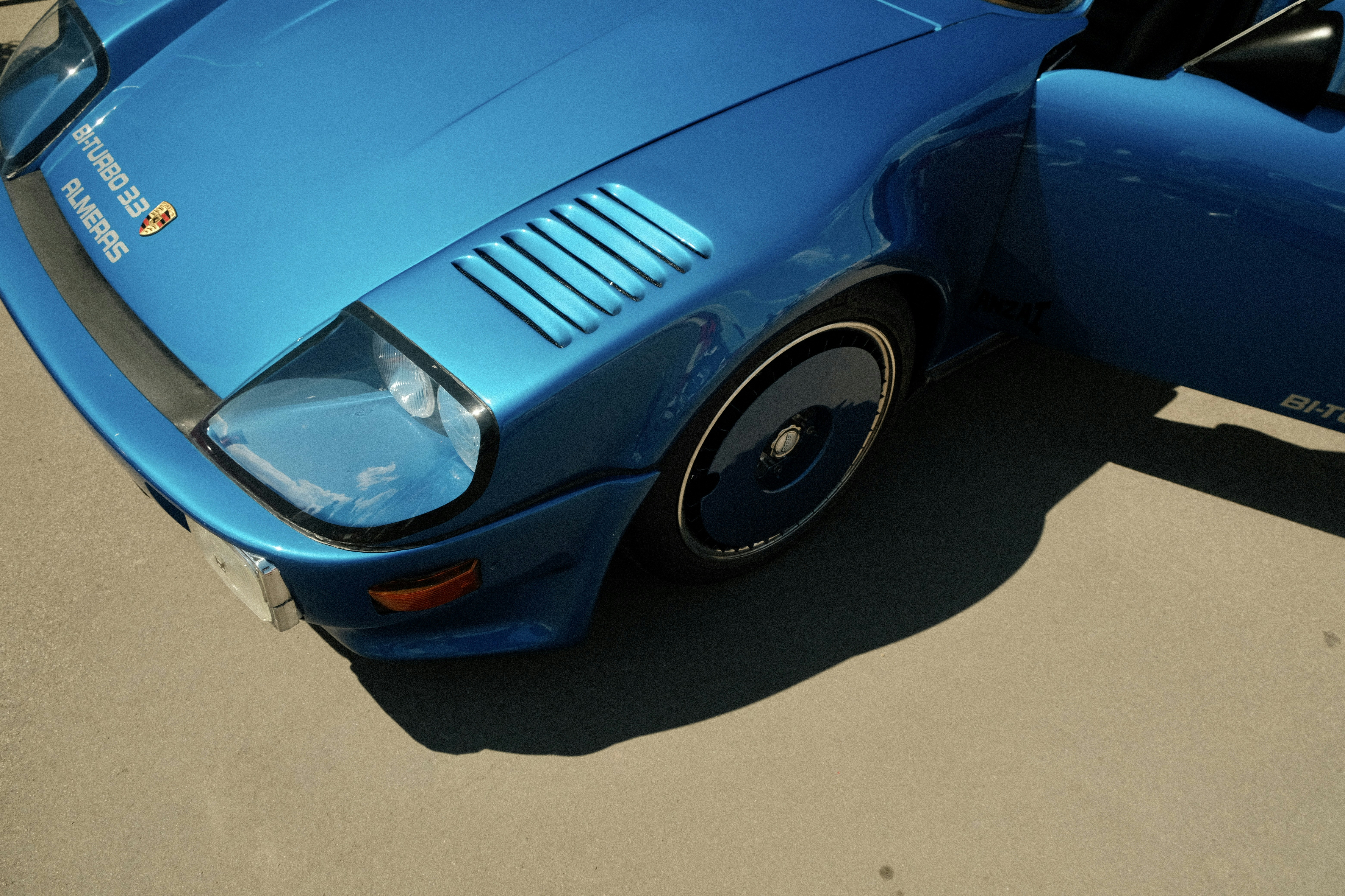 Classic blue sports car showcasing sleek lines and vintage charm, parked with door ajar. Emphasizes the vehicle's distinctive design features.