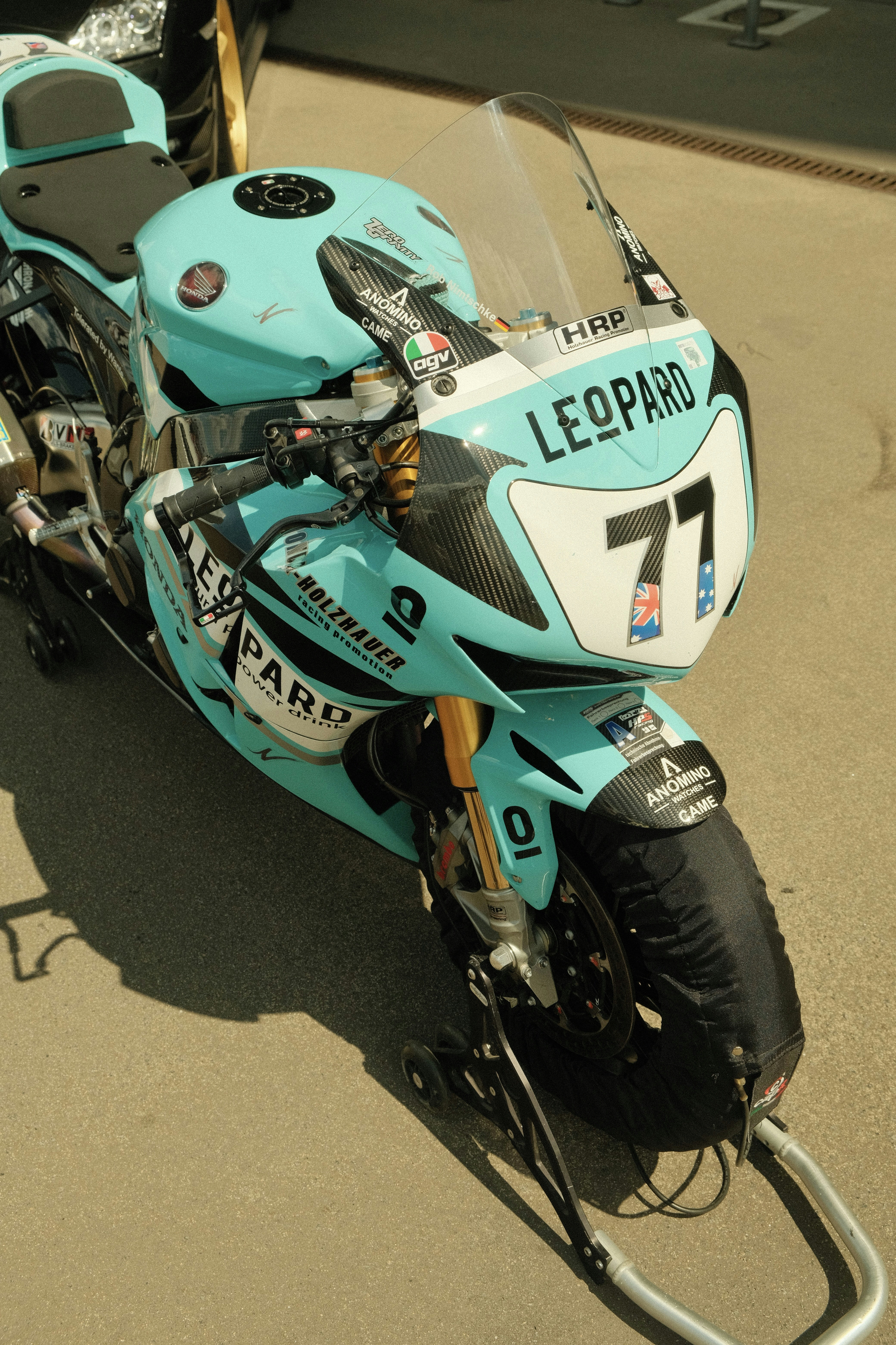 Turquoise Racetrack: Leopard livery motorcycle under sunlit pit shade