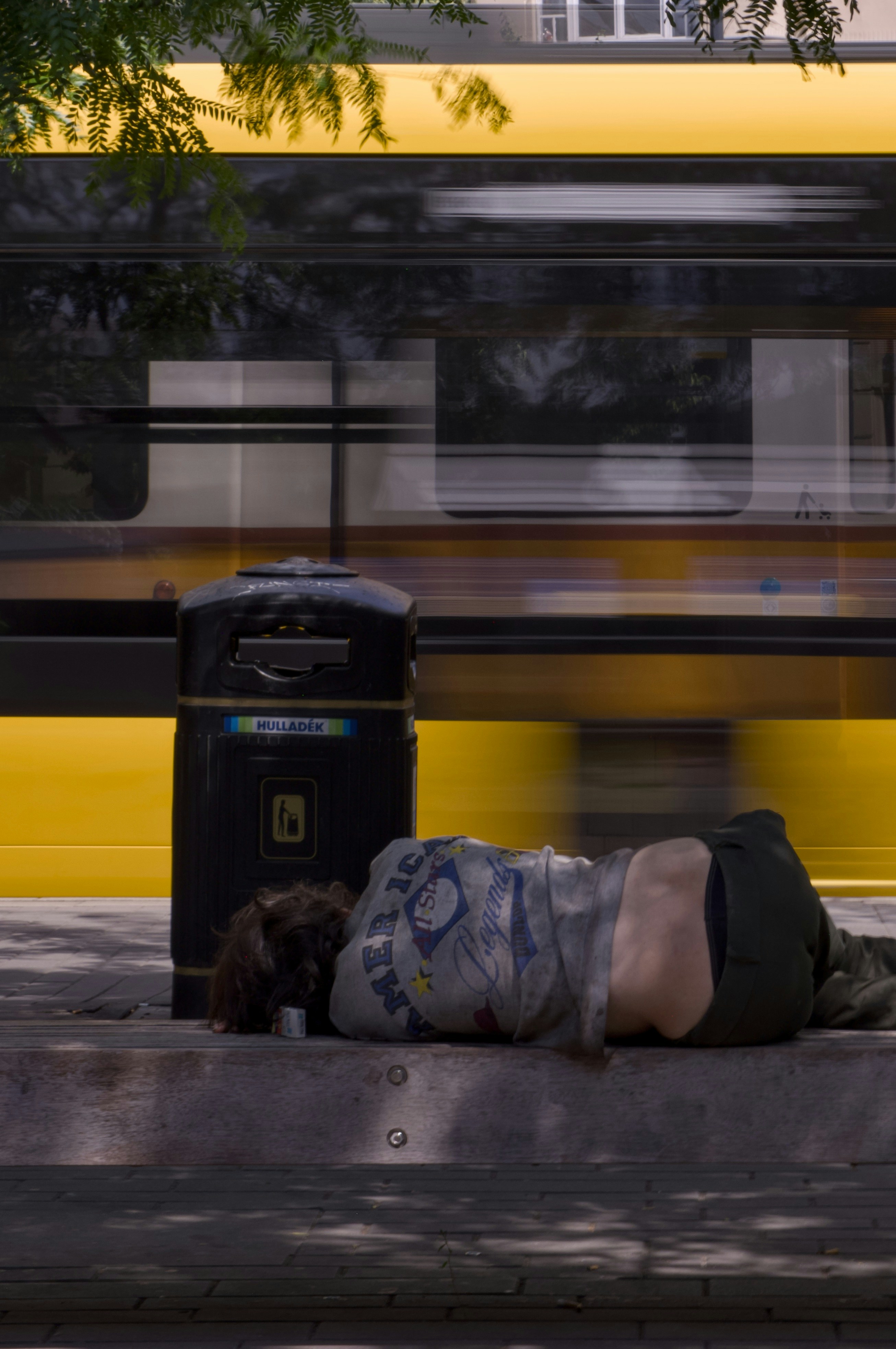 A homeless person sleeps near a bus.