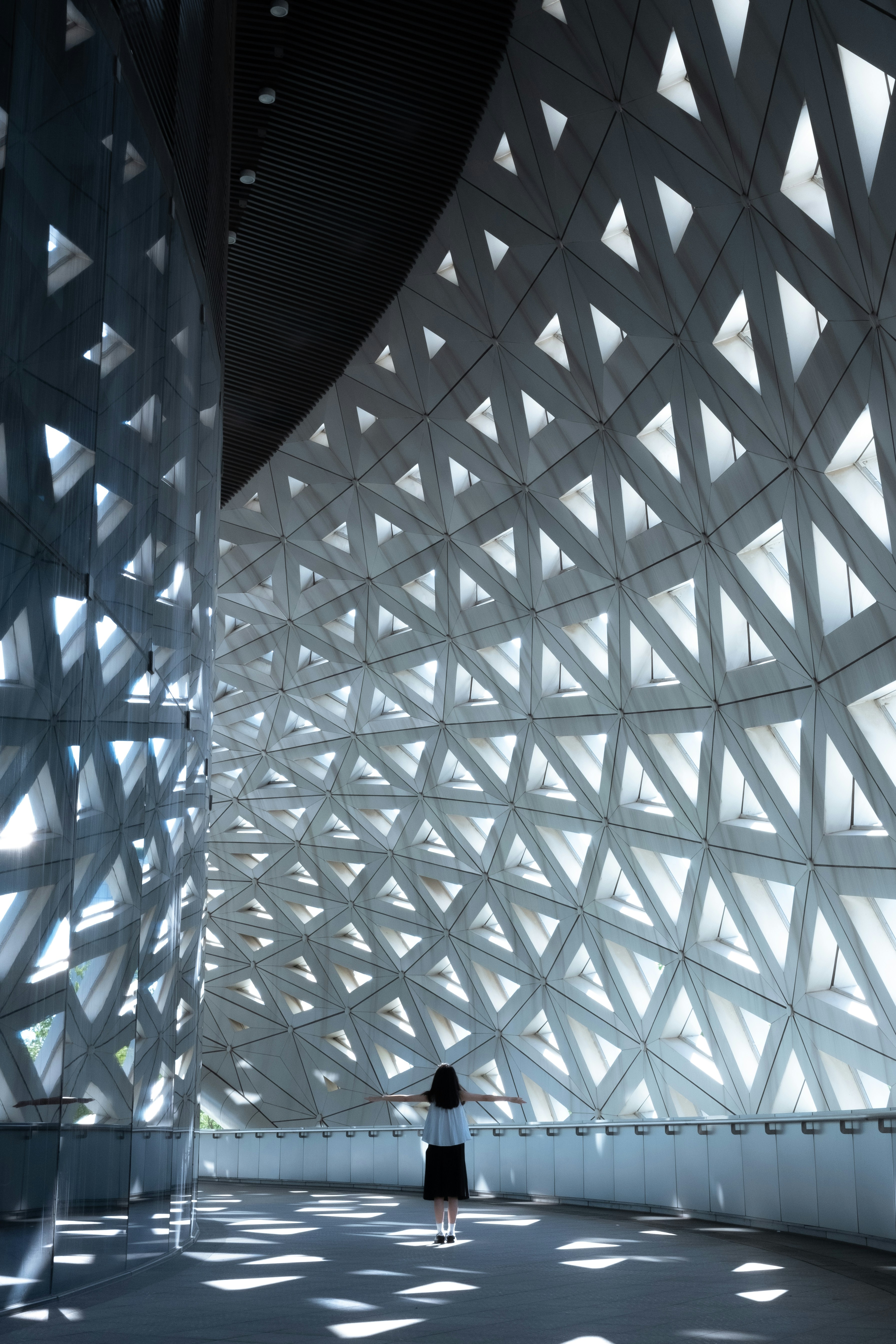 A person stands in a geometric architectural space.