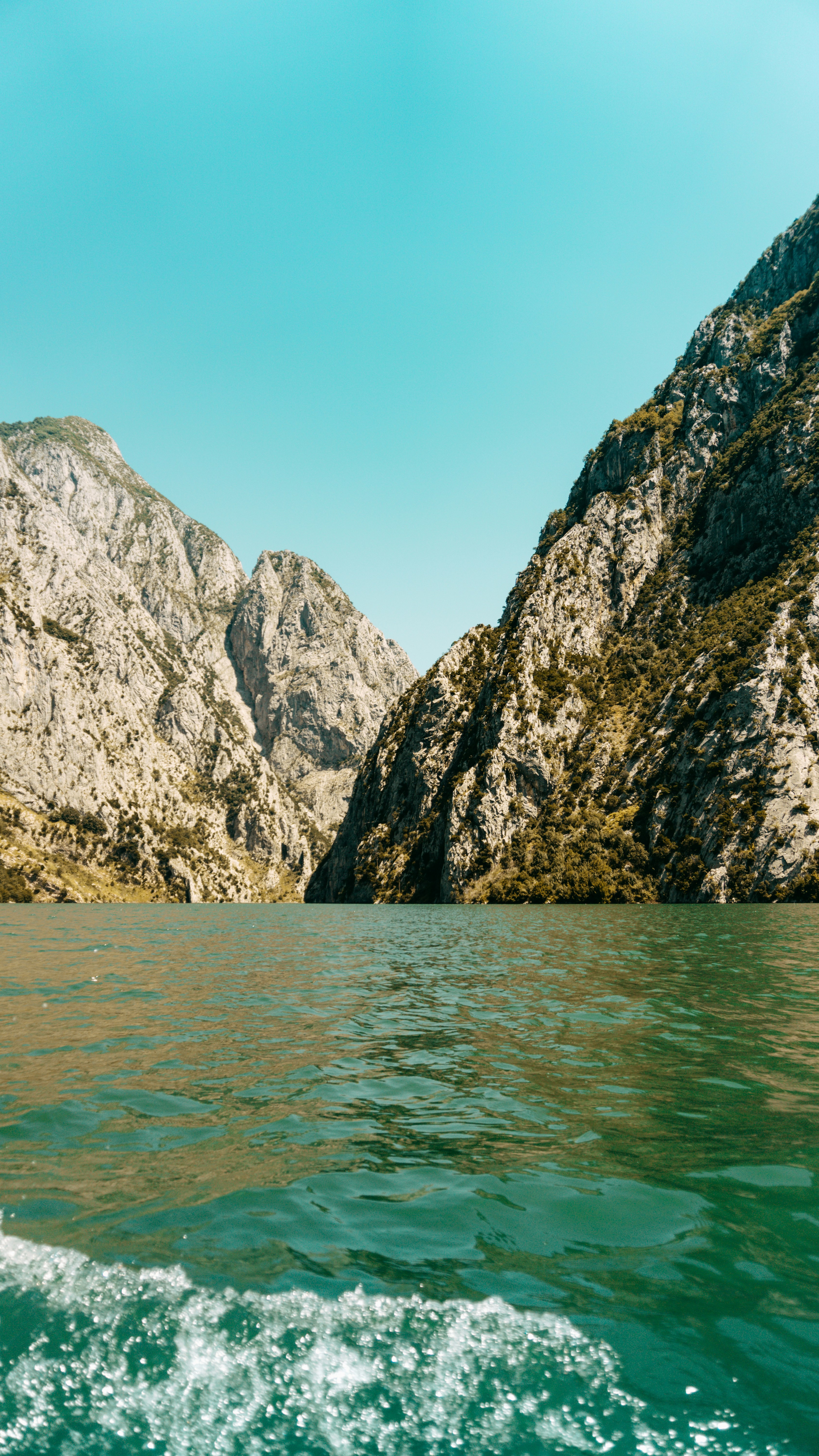 Vast turquoise waters reflect towering cliffs under a clear sky, showcasing the harmony of nature's elements.