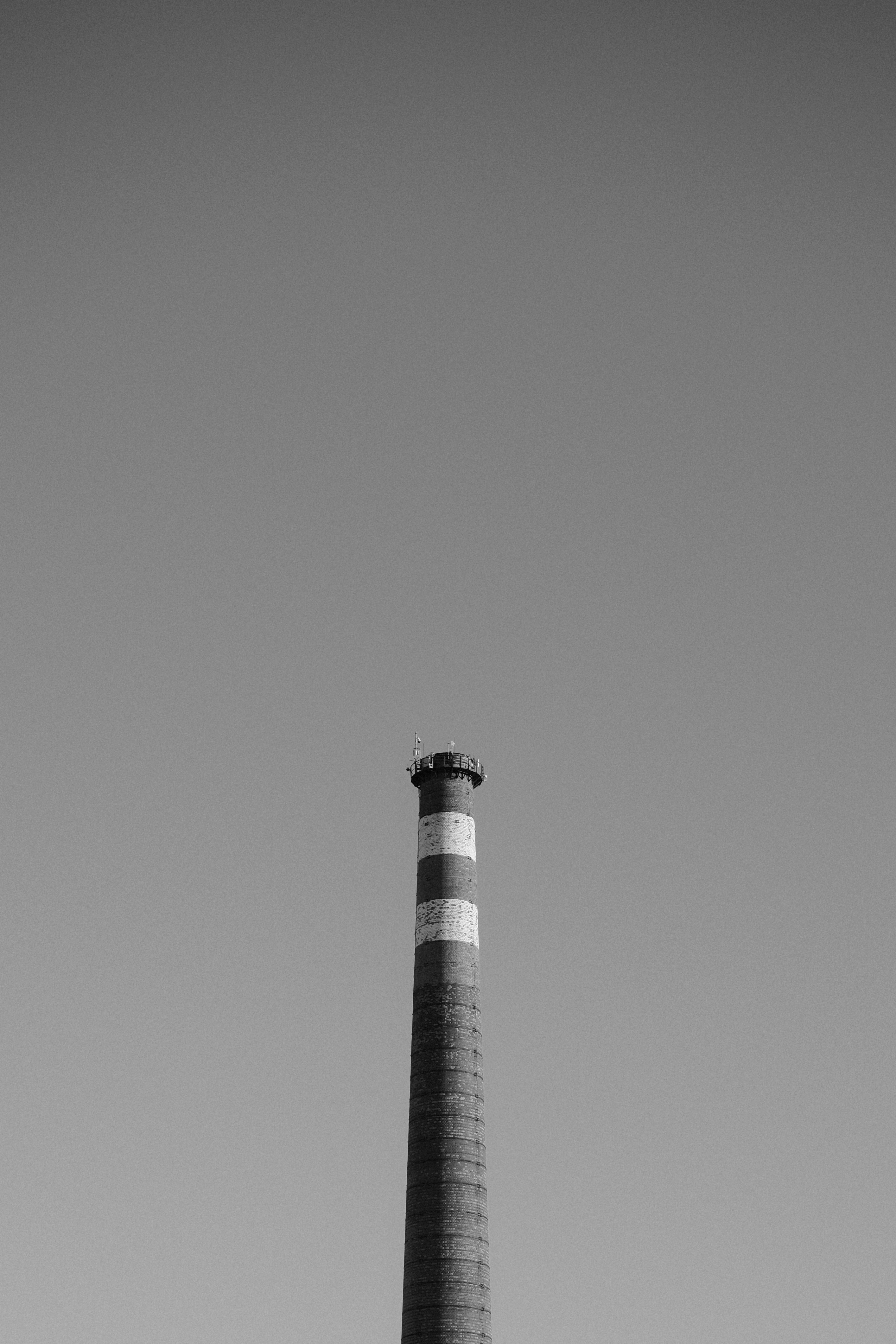 Tall industrial smokestack against a clear sky | A tall chimney stands against a clear sky.
