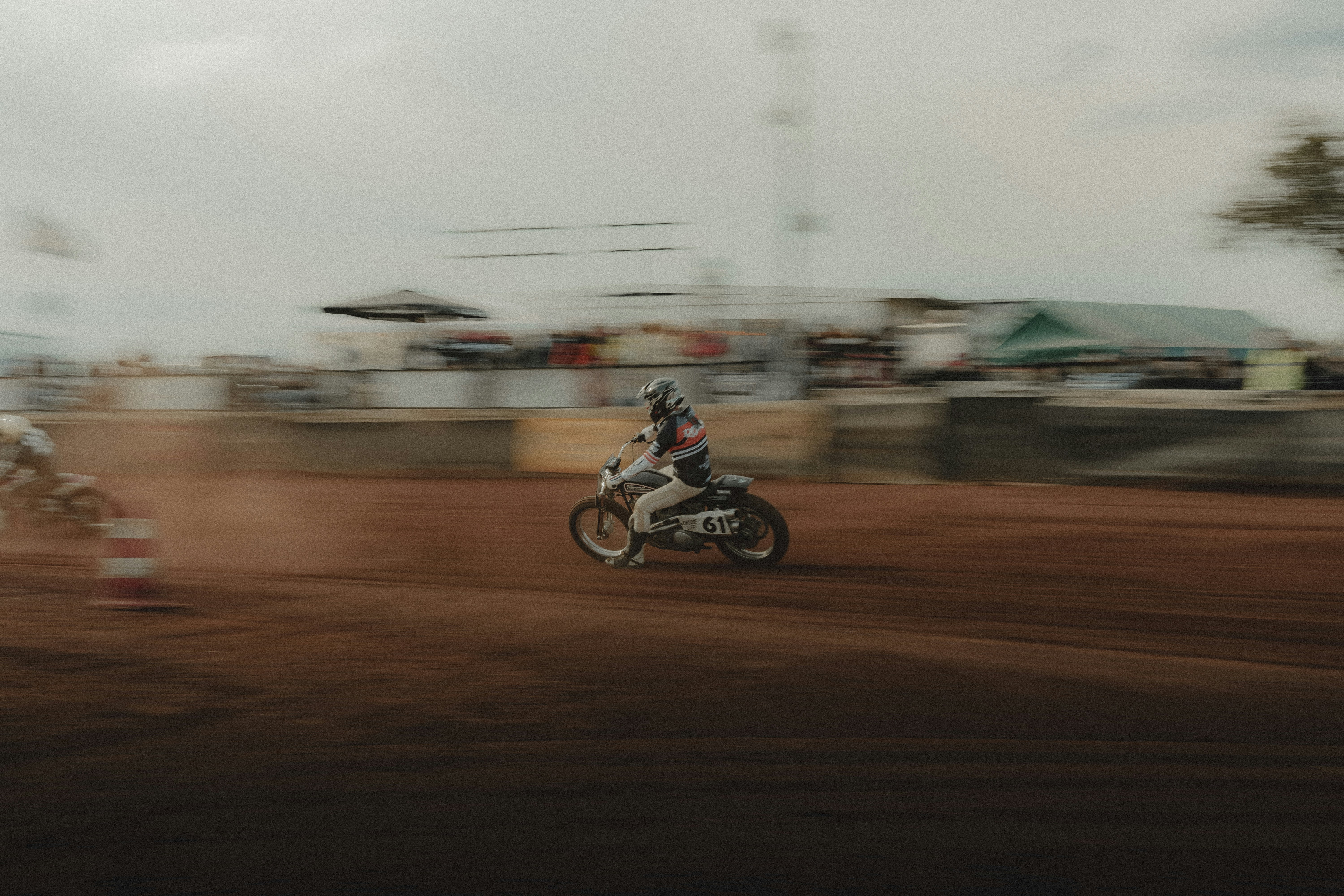 Motorcycle racers speed around a dirt track.