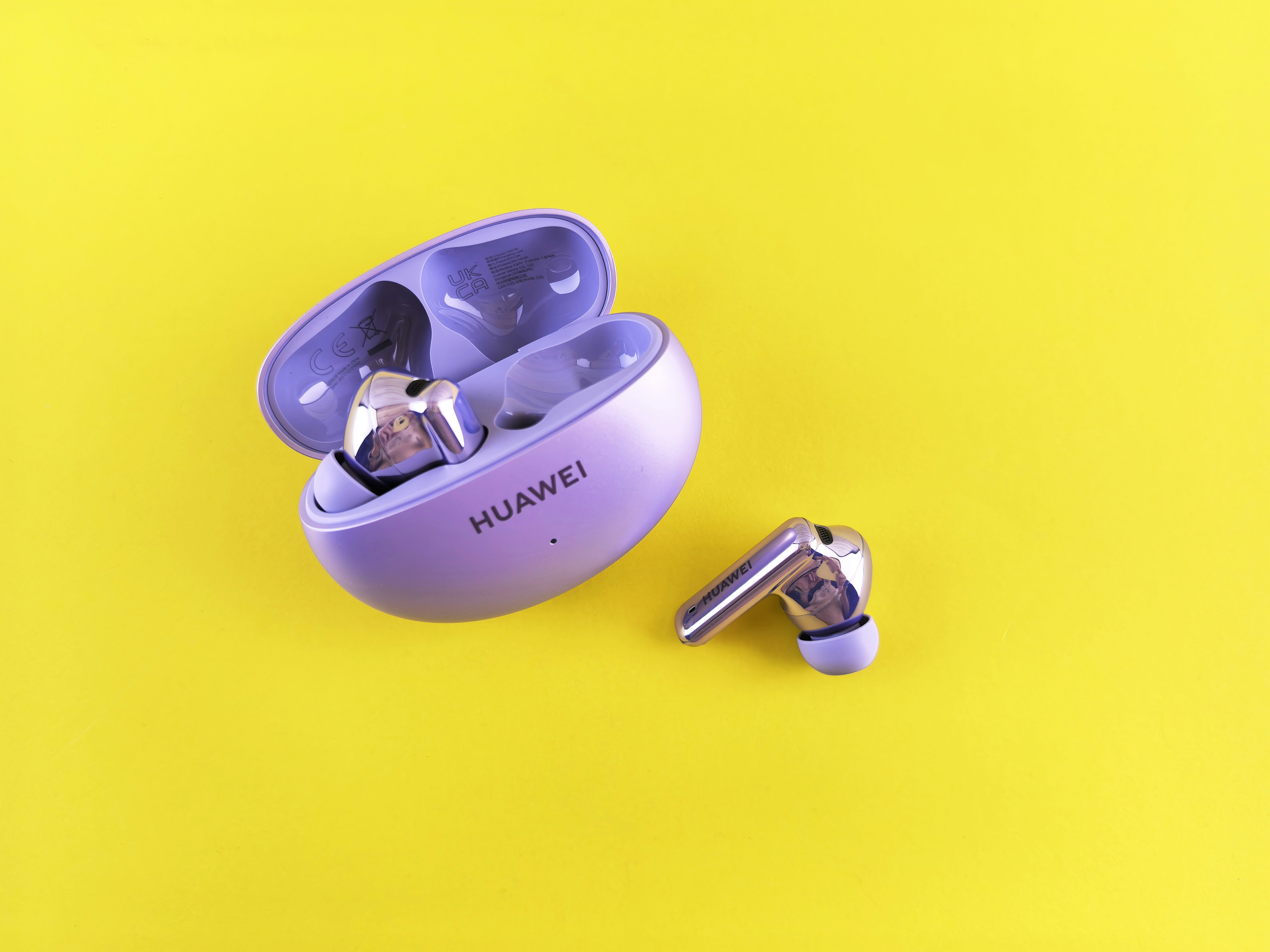 Huawei earbuds on a yellow surface.