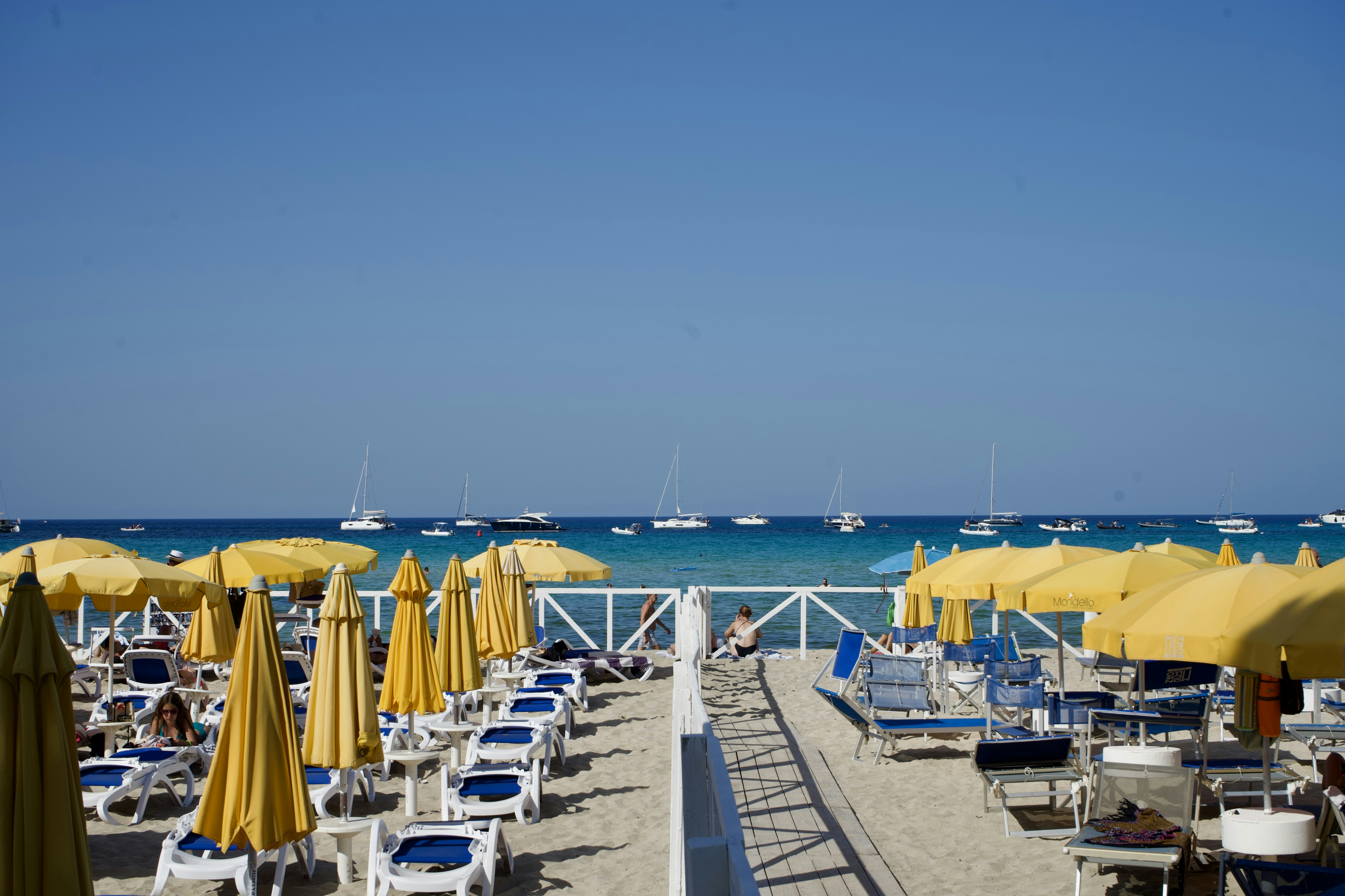Beachfront Corridor: Rows of Yellow Umbrellas Framing a Quiet Walk Toward the Sea