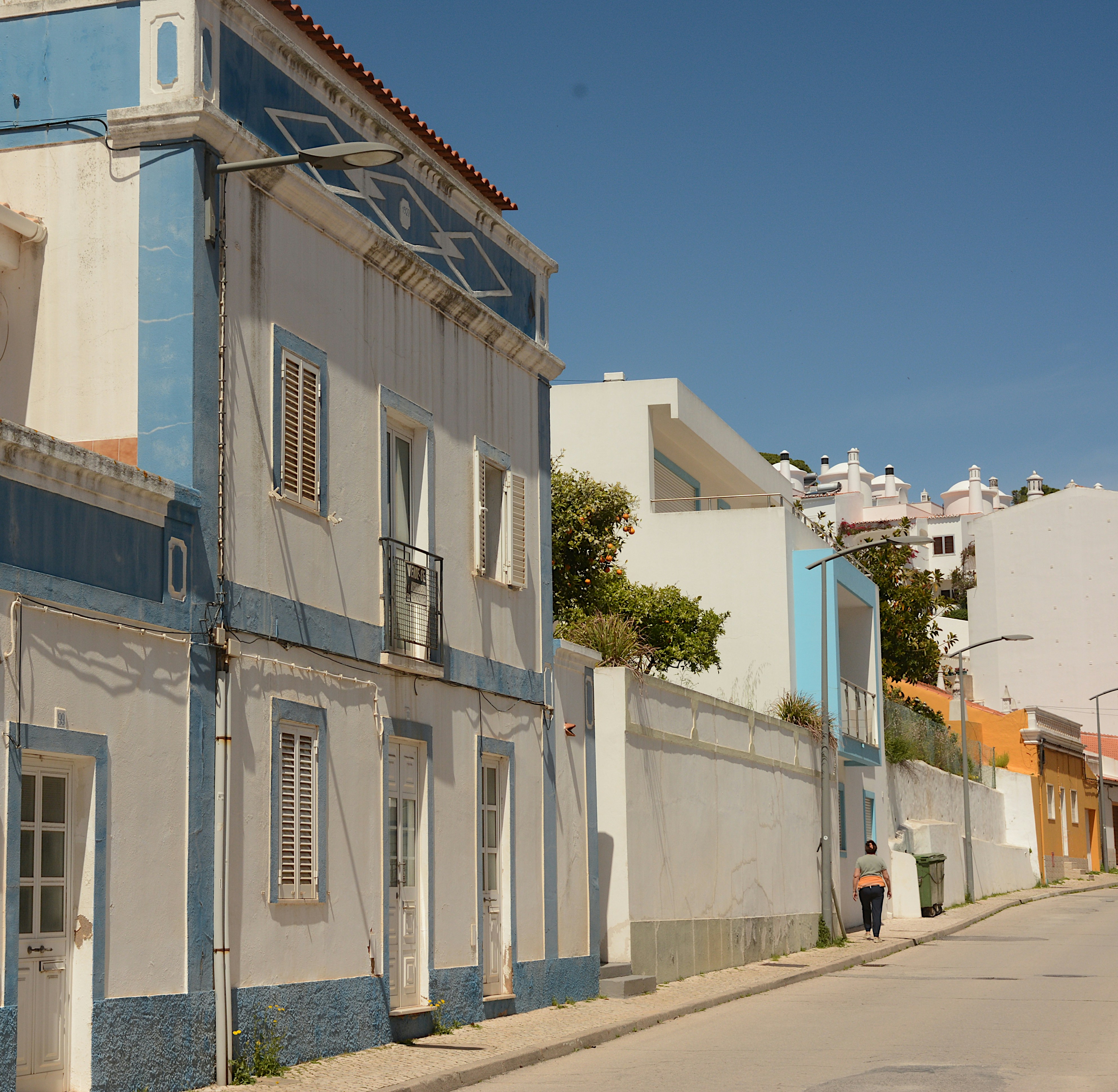 Carvoeiro. | Homes line a street under a clear, blue sky.