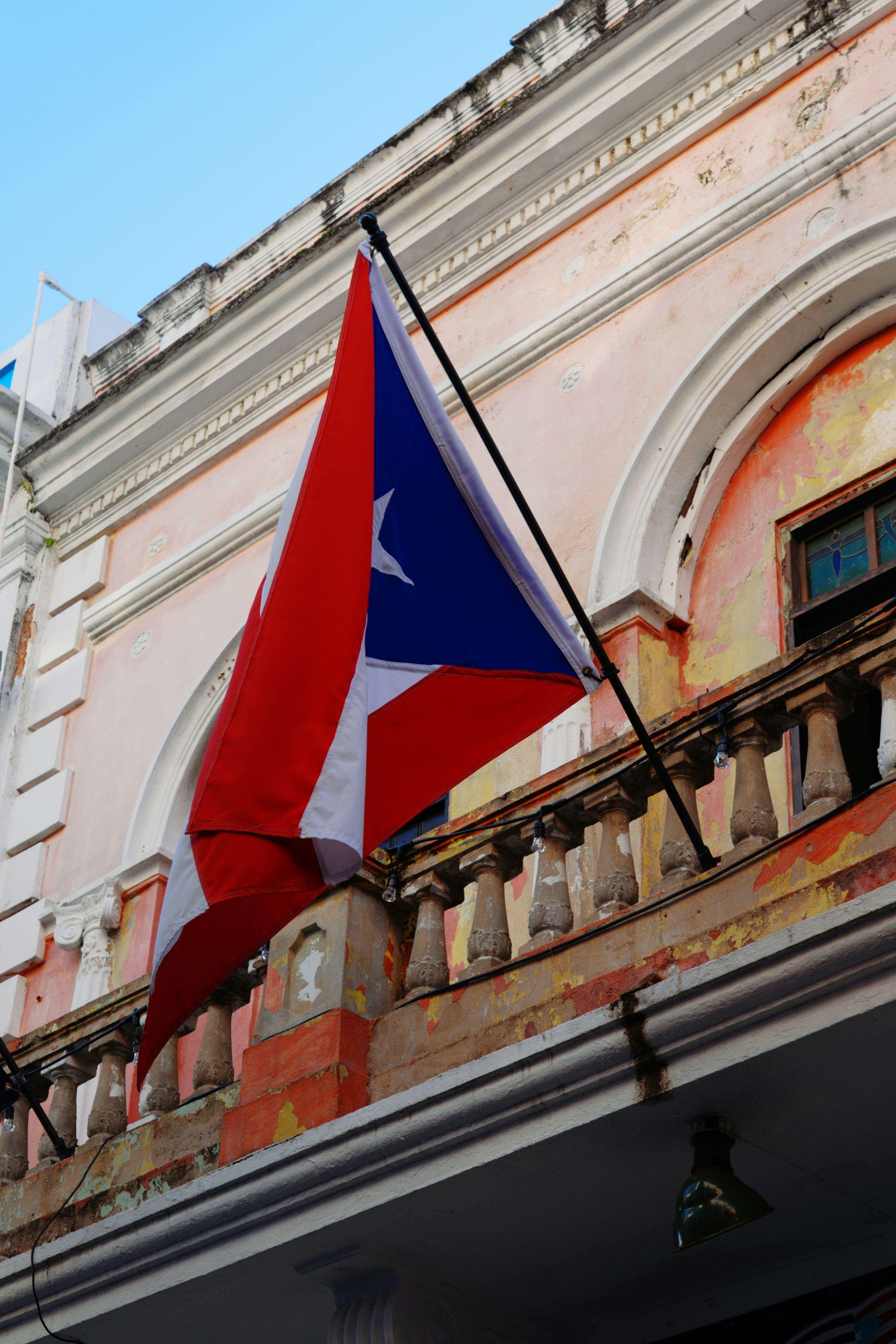 A puerto rican flag waves on a building.