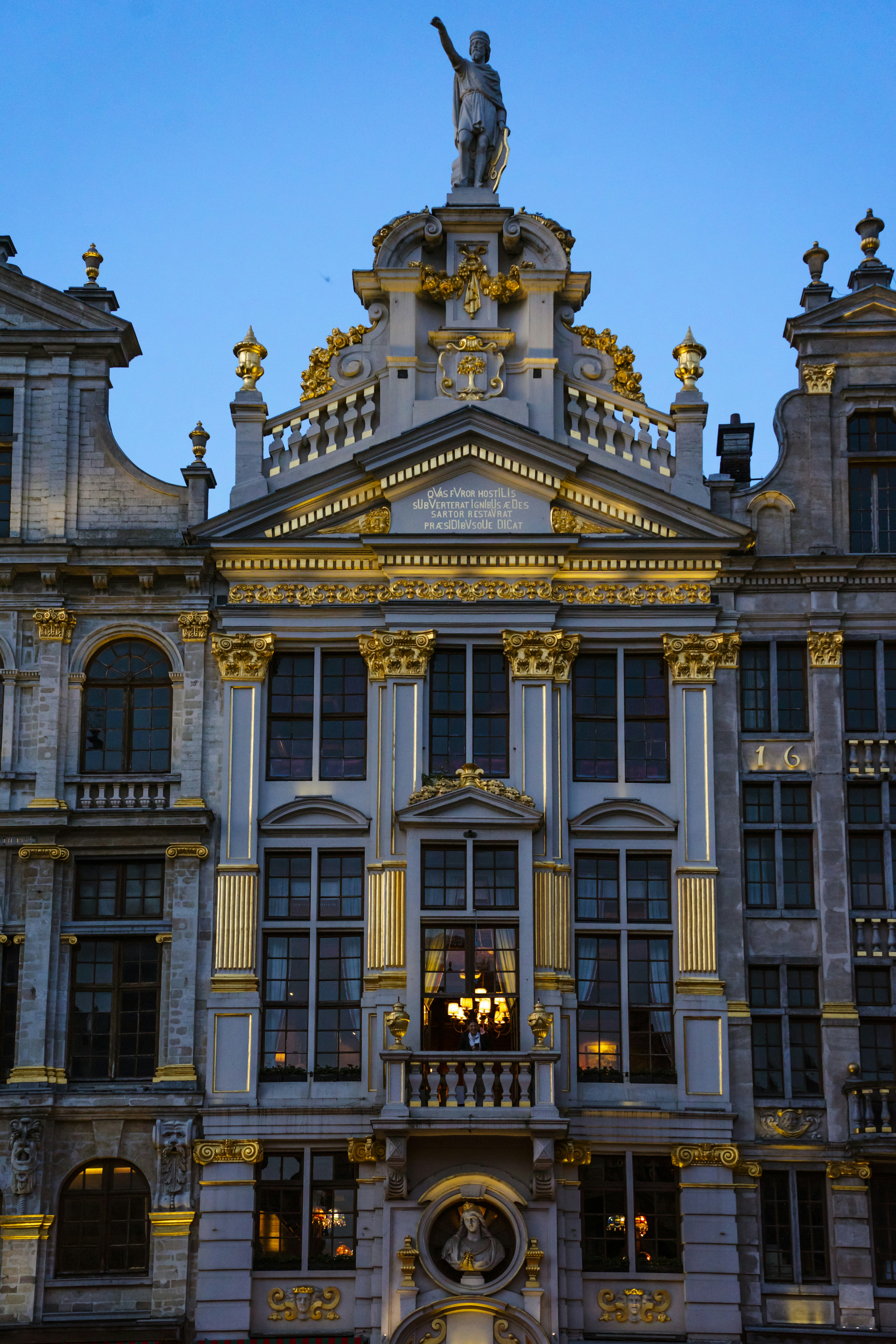 Ornately decorated building in Brussels showcasing intricate gold detailing and a prominent statue atop its façade.