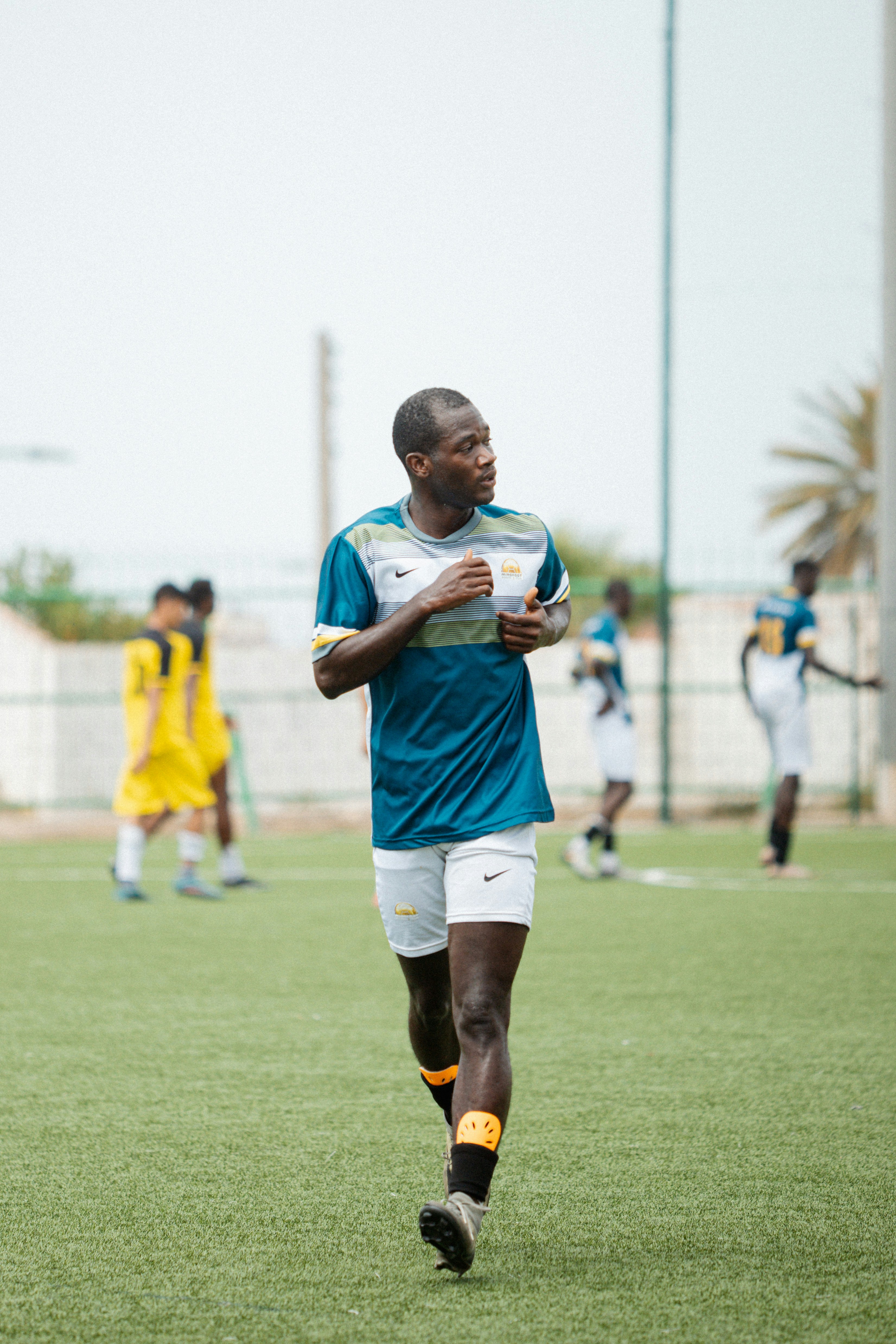 Midfield Moment: A Focused Player Strides Across a Sunlit Training Pitch