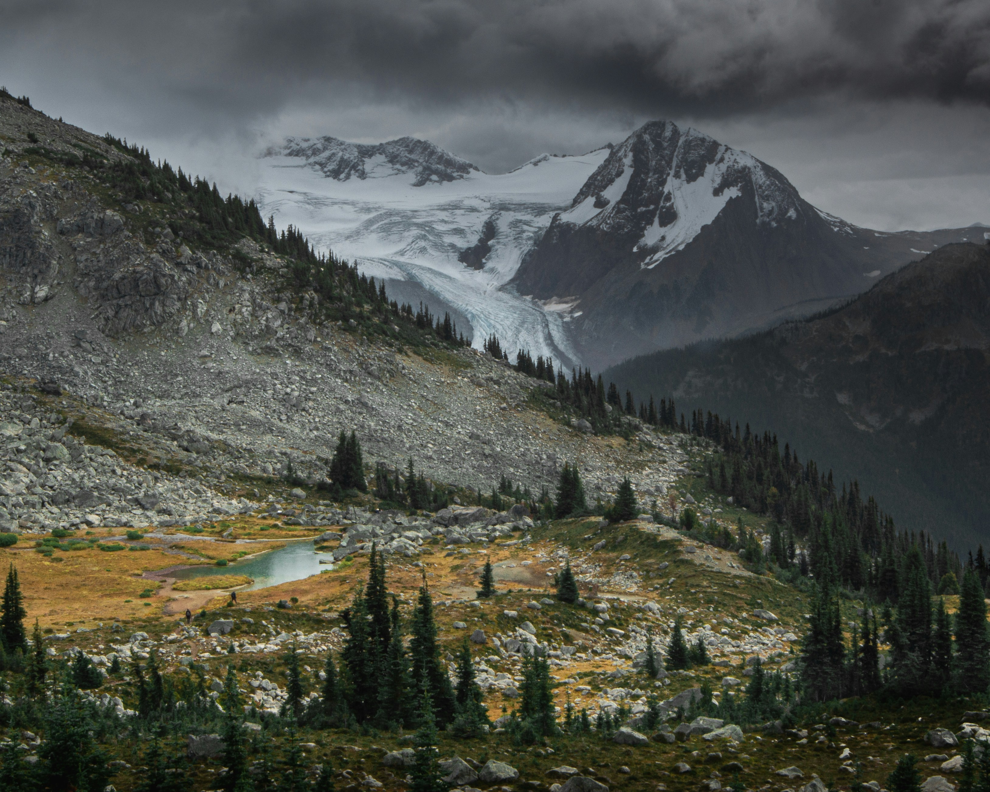 Storm-Clouded Alps Over Alpine Meadow and Glacial Tarn