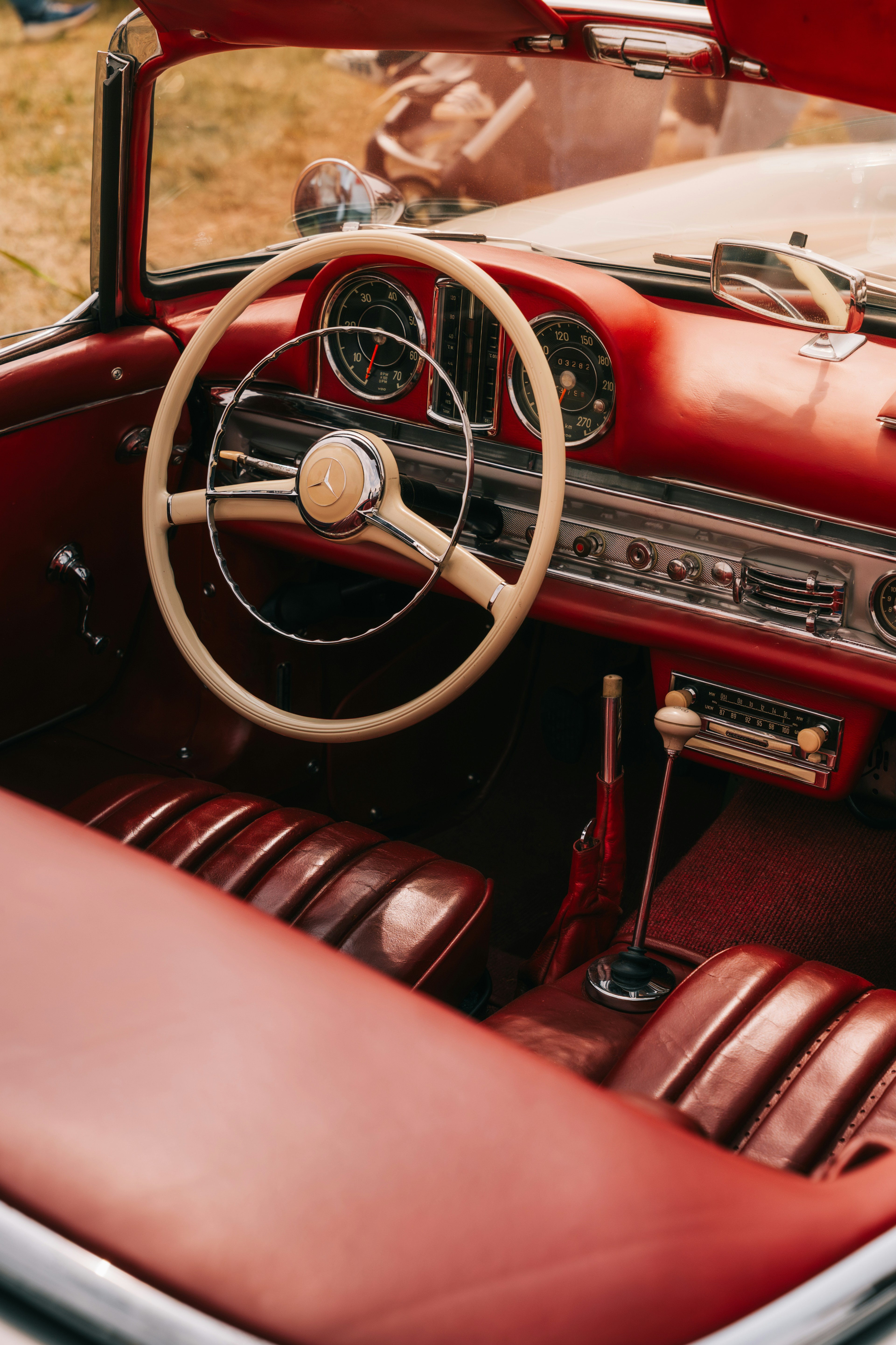 Vintage car interior showcasing a luxurious dashboard with a prominent steering wheel and rich leather seating. The design reflects a blend of nostalgia and craftsmanship.