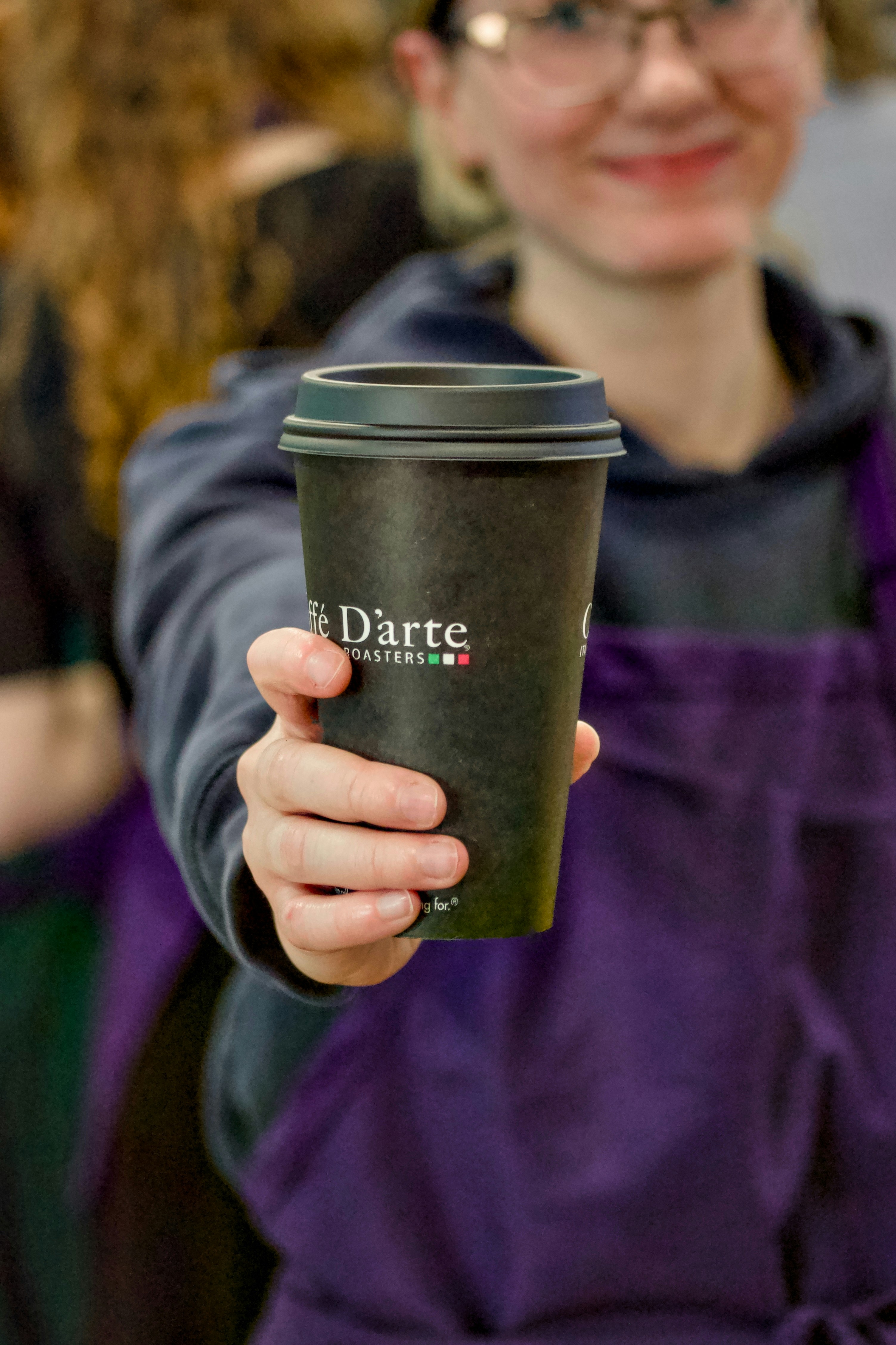 Here's a caption: someone offers a cup of coffee.