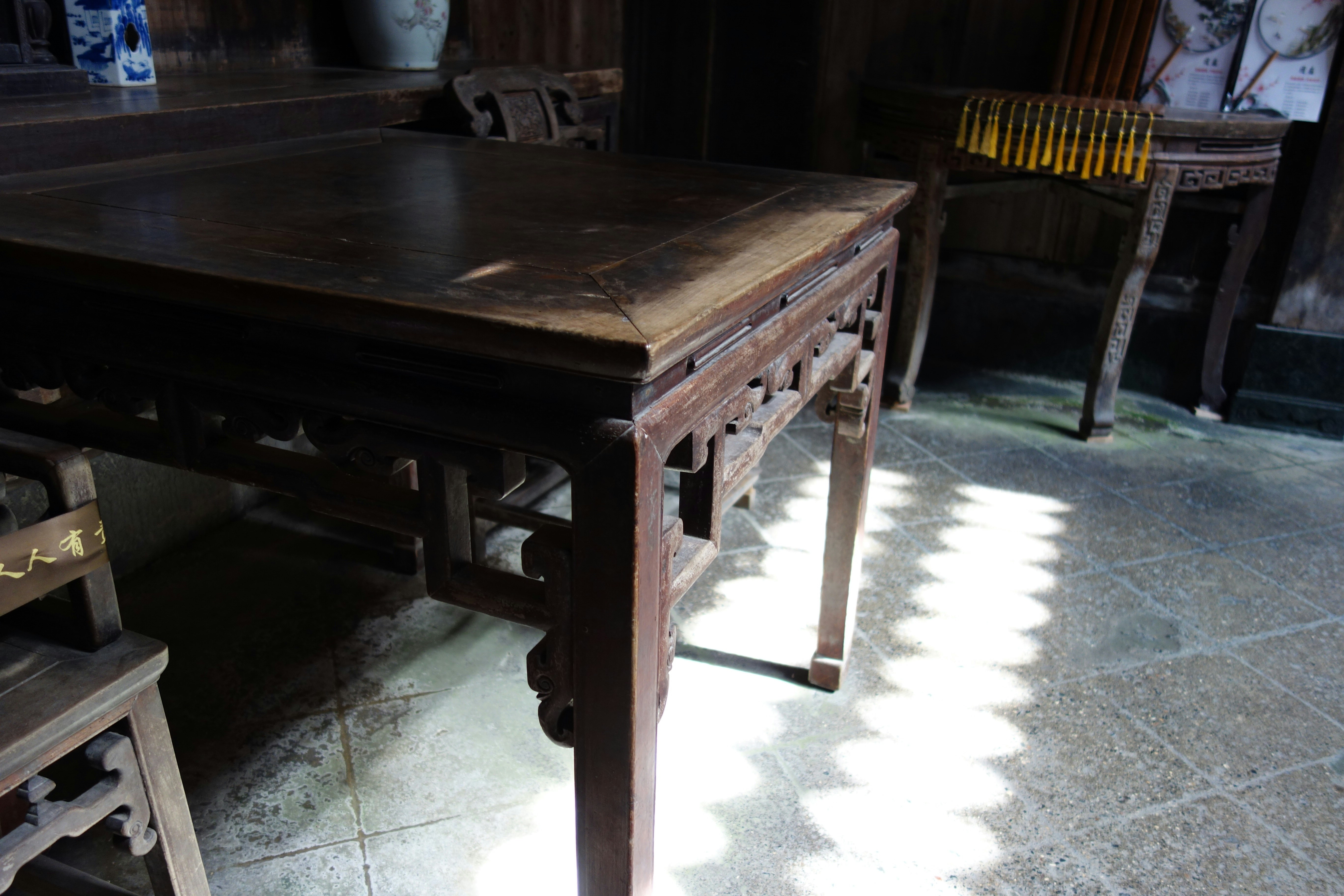 Lattice Sunlight Illuminates a Carved Wooden Table in a Quiet Interior