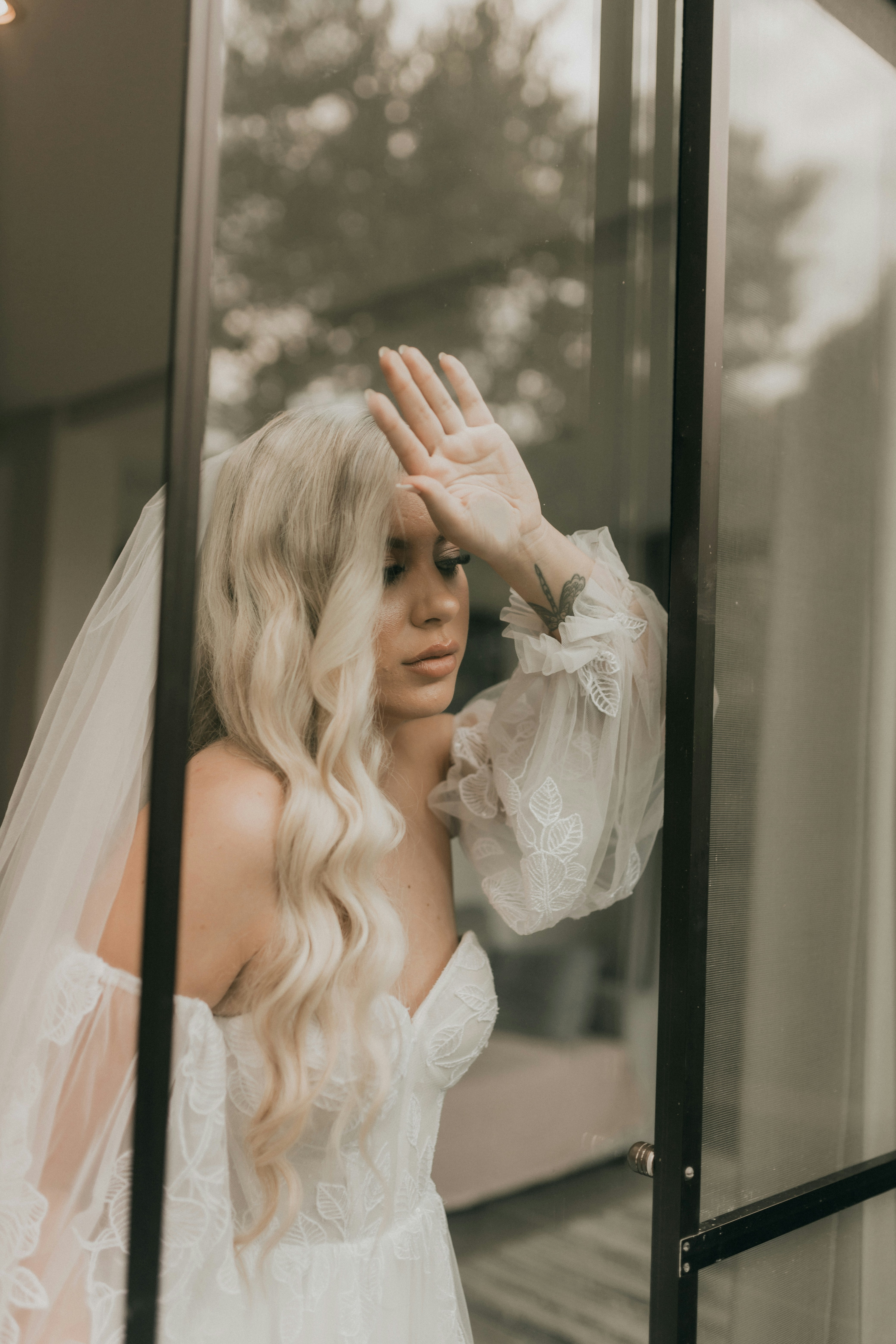 A bride gazes through a glass door.