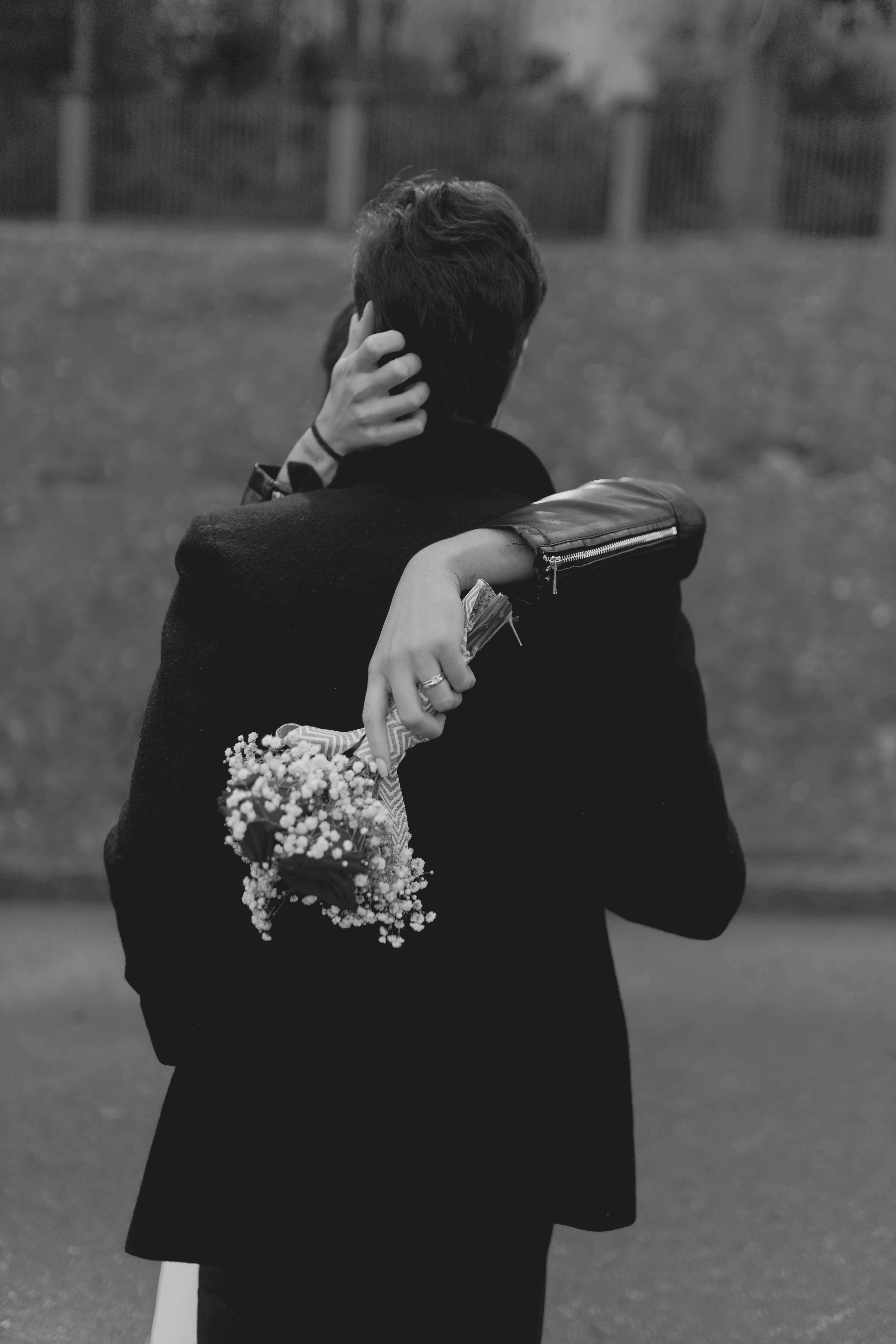 Couple sharing an intimate moment, with one partner holding a bouquet while embracing the other. A sense of love and connection fills the scene.