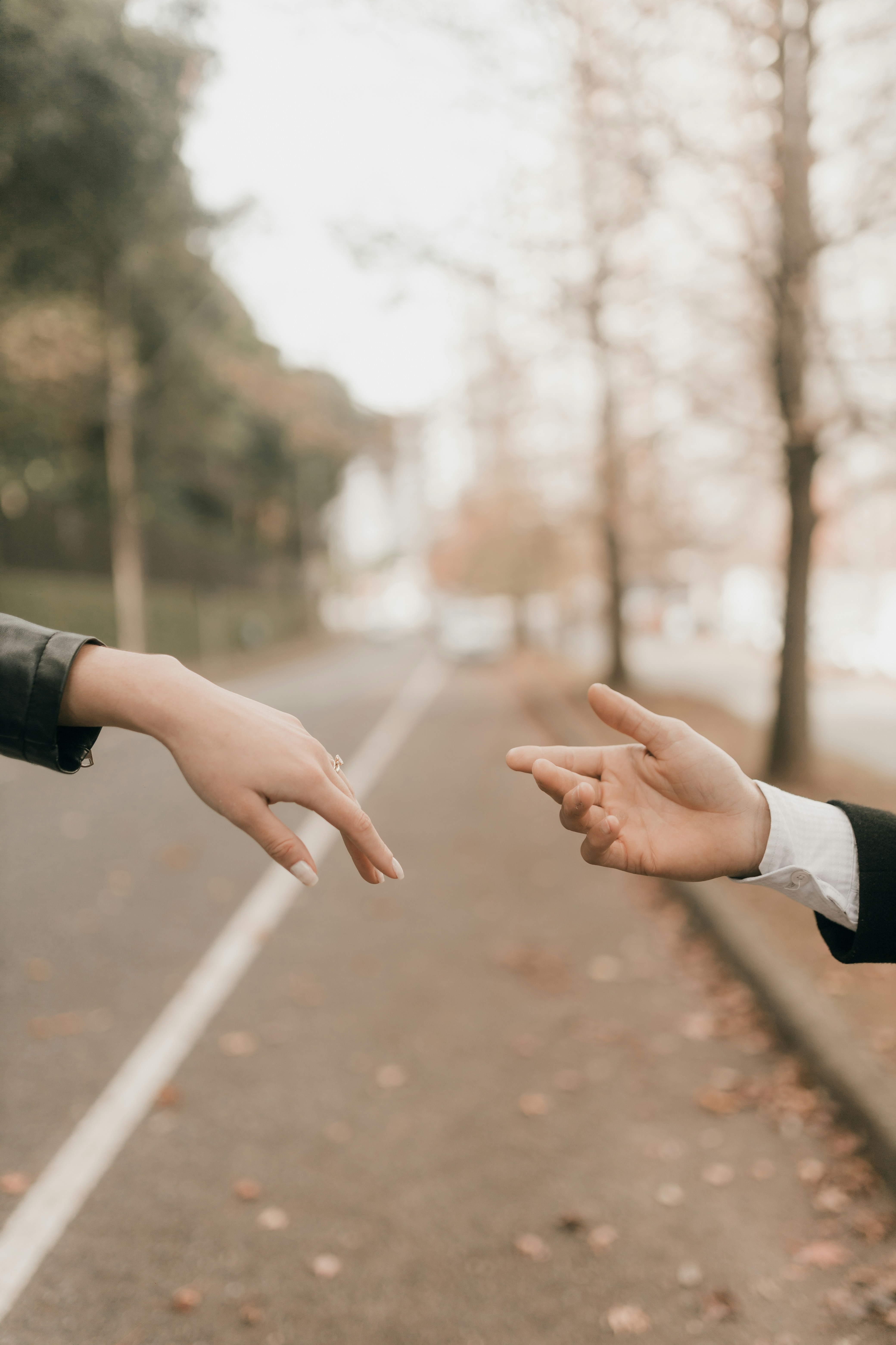 Two hands reaching towards each other on a quiet street, symbolizing connection and intimacy.