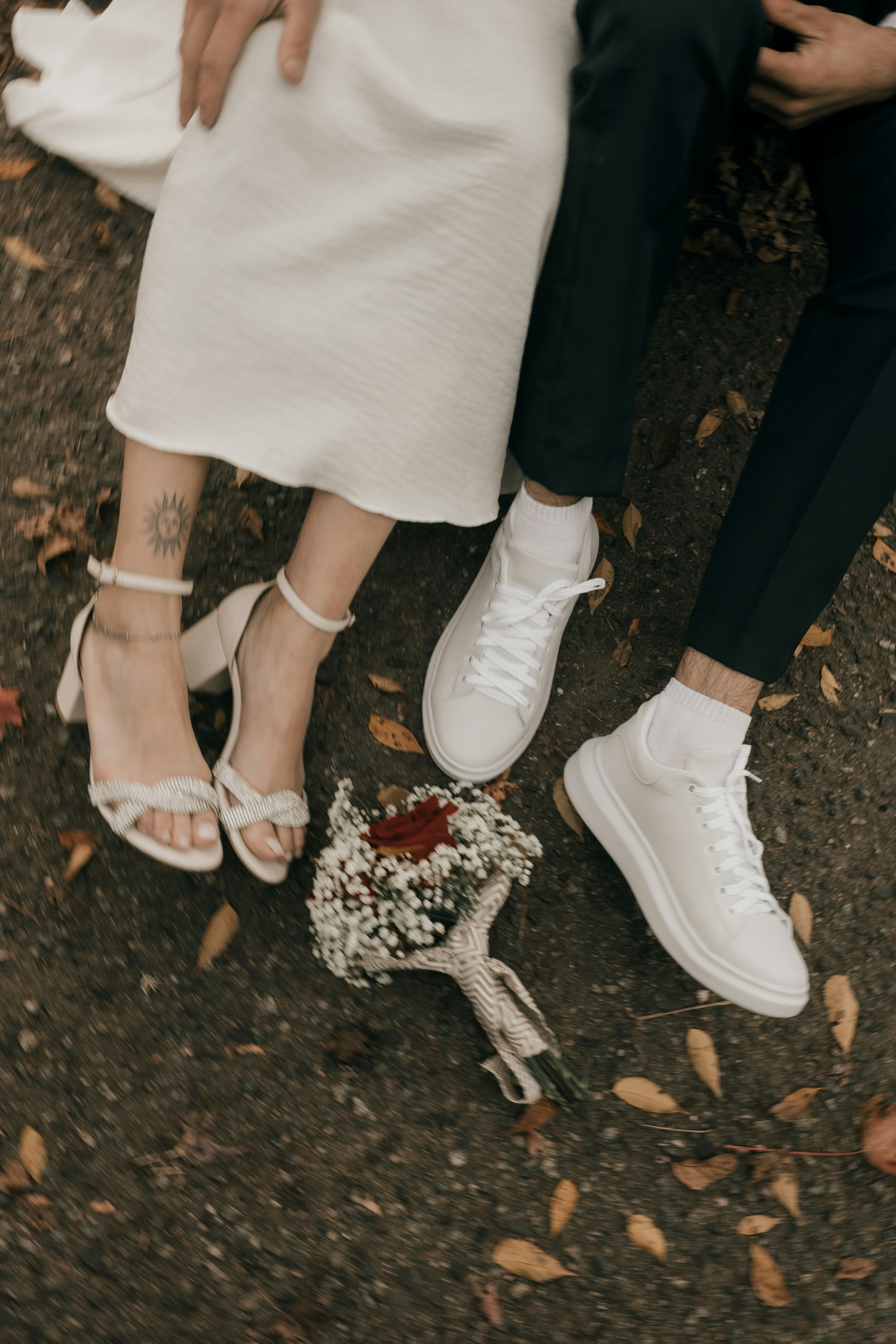 Grounded Vows: bouquet resting between bridal heels and groom’s sneakers