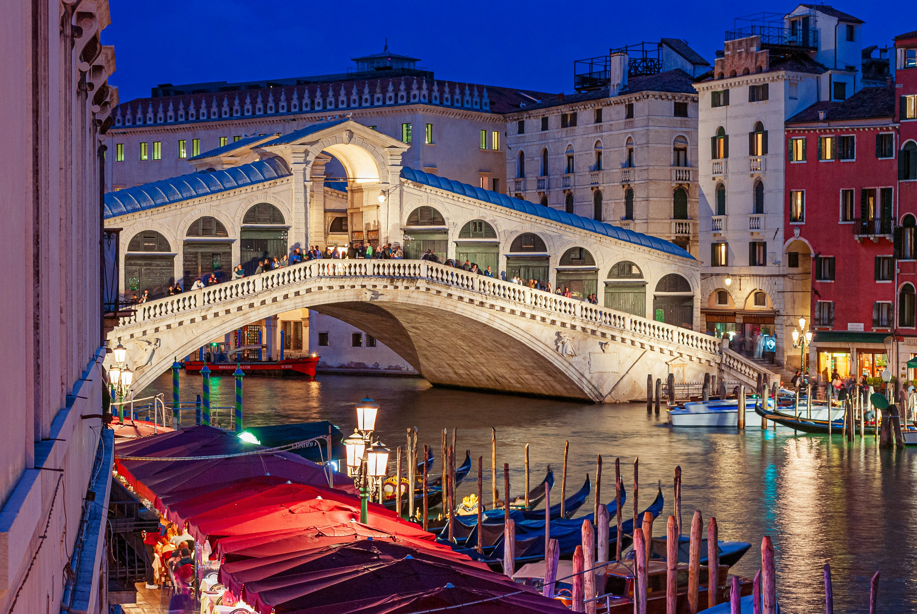 The Rialto Bridge in the evening. | The rialto bridge over a venetian canal at night.