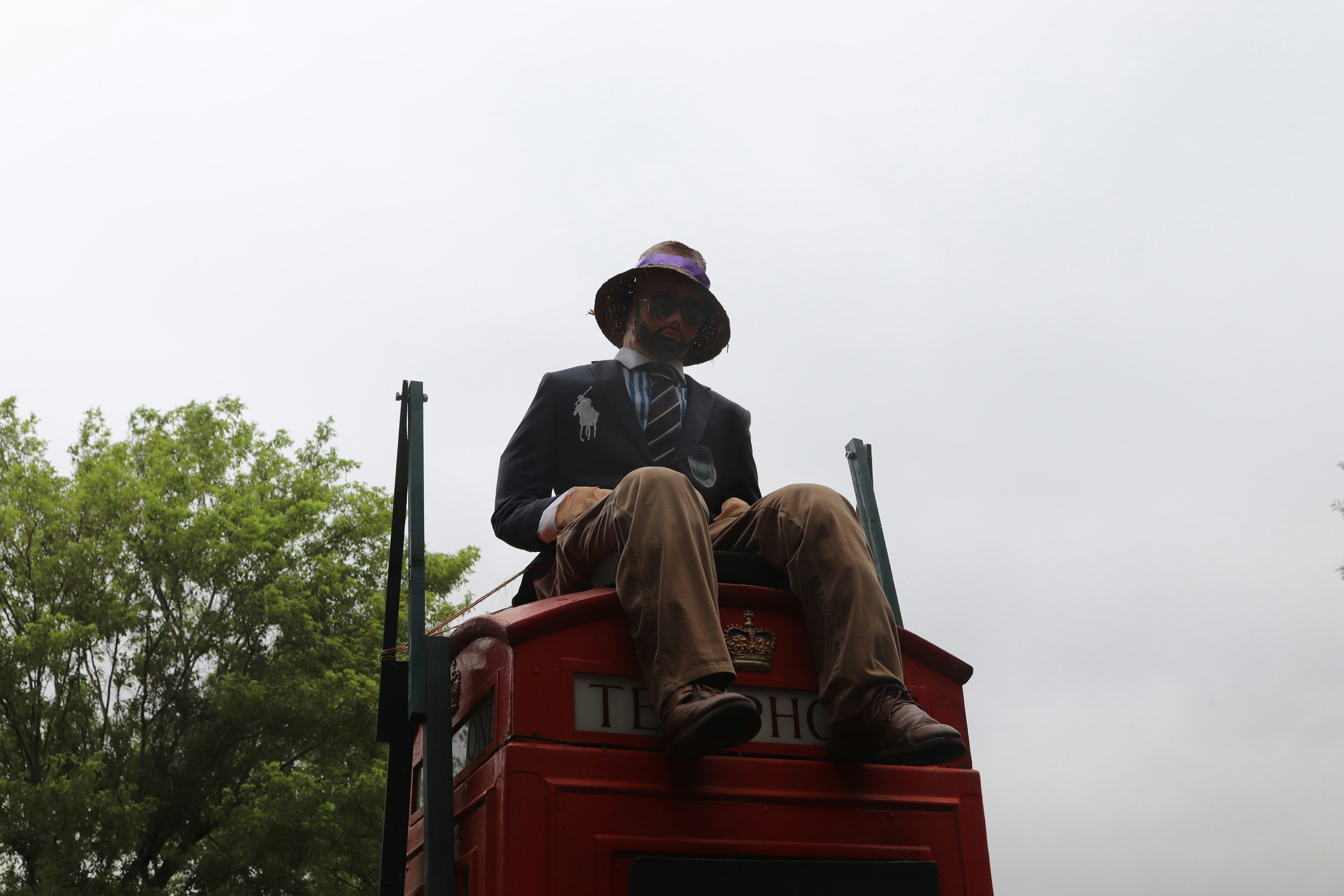A figure sits atop a red telephone booth. photo – Free Man Image on ...