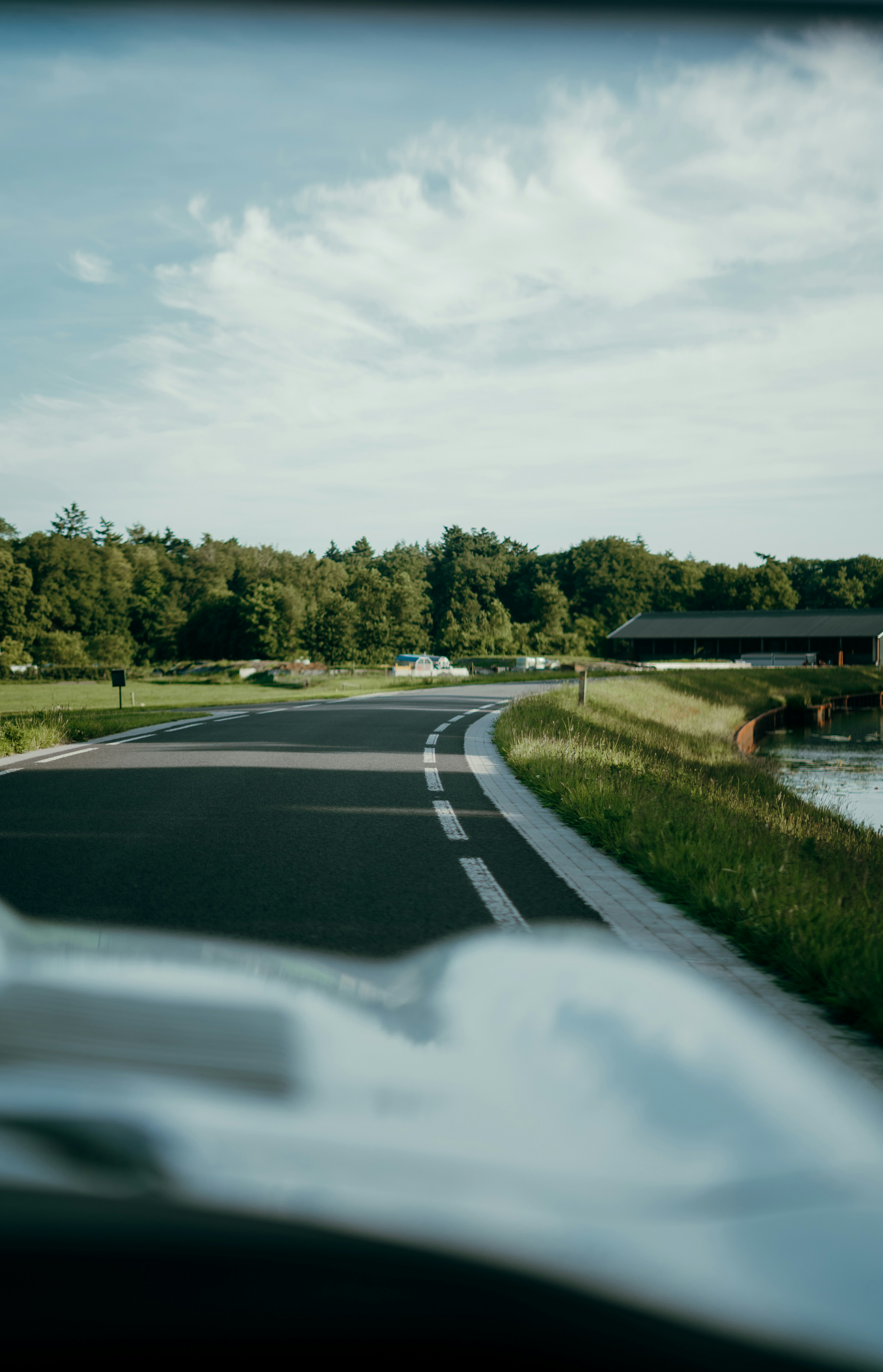 Riverside Curve: A Daylight Drive Toward the Bridge by Calm Water
