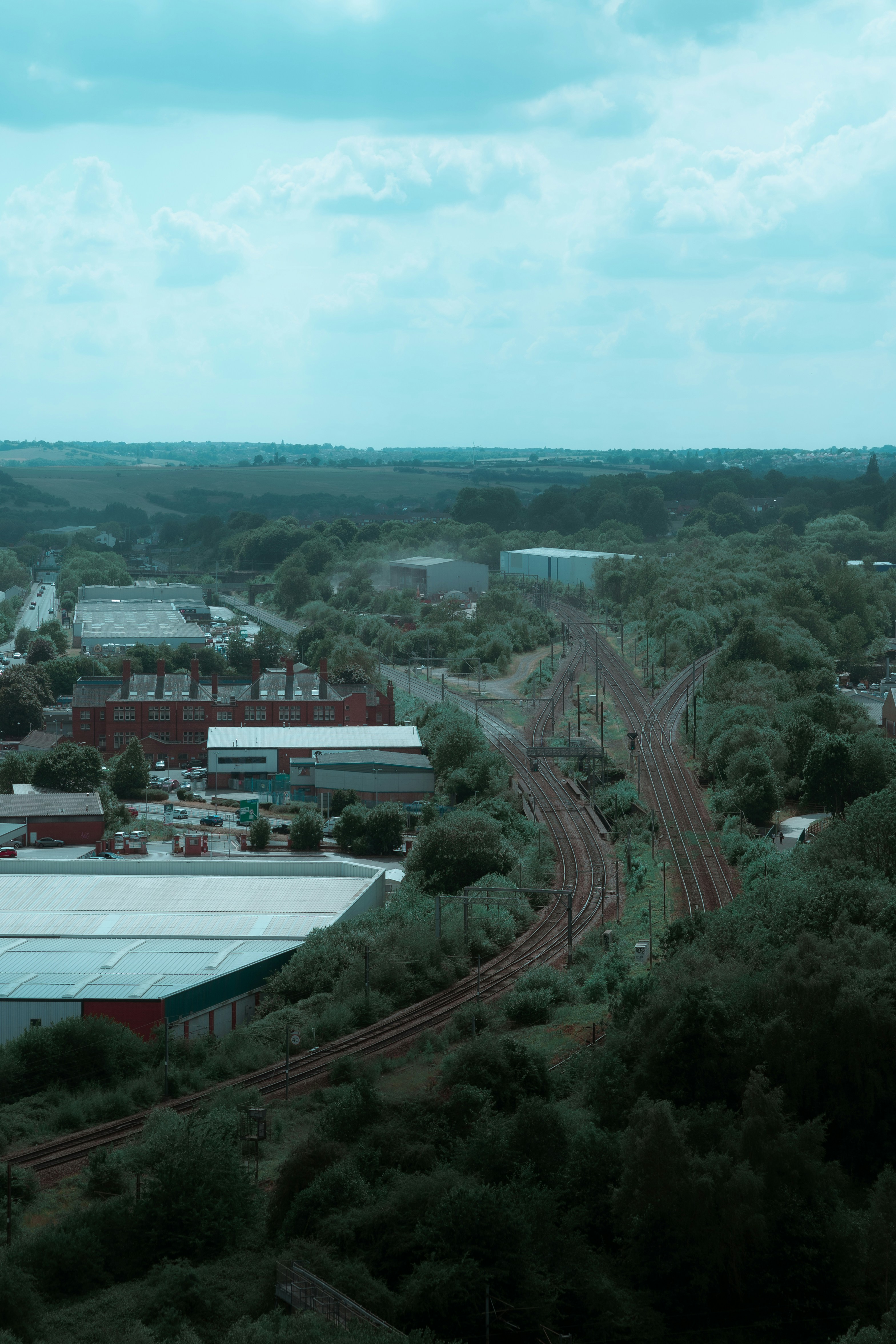 railway lines in Leeds | Train tracks curve through a lush, green landscape.