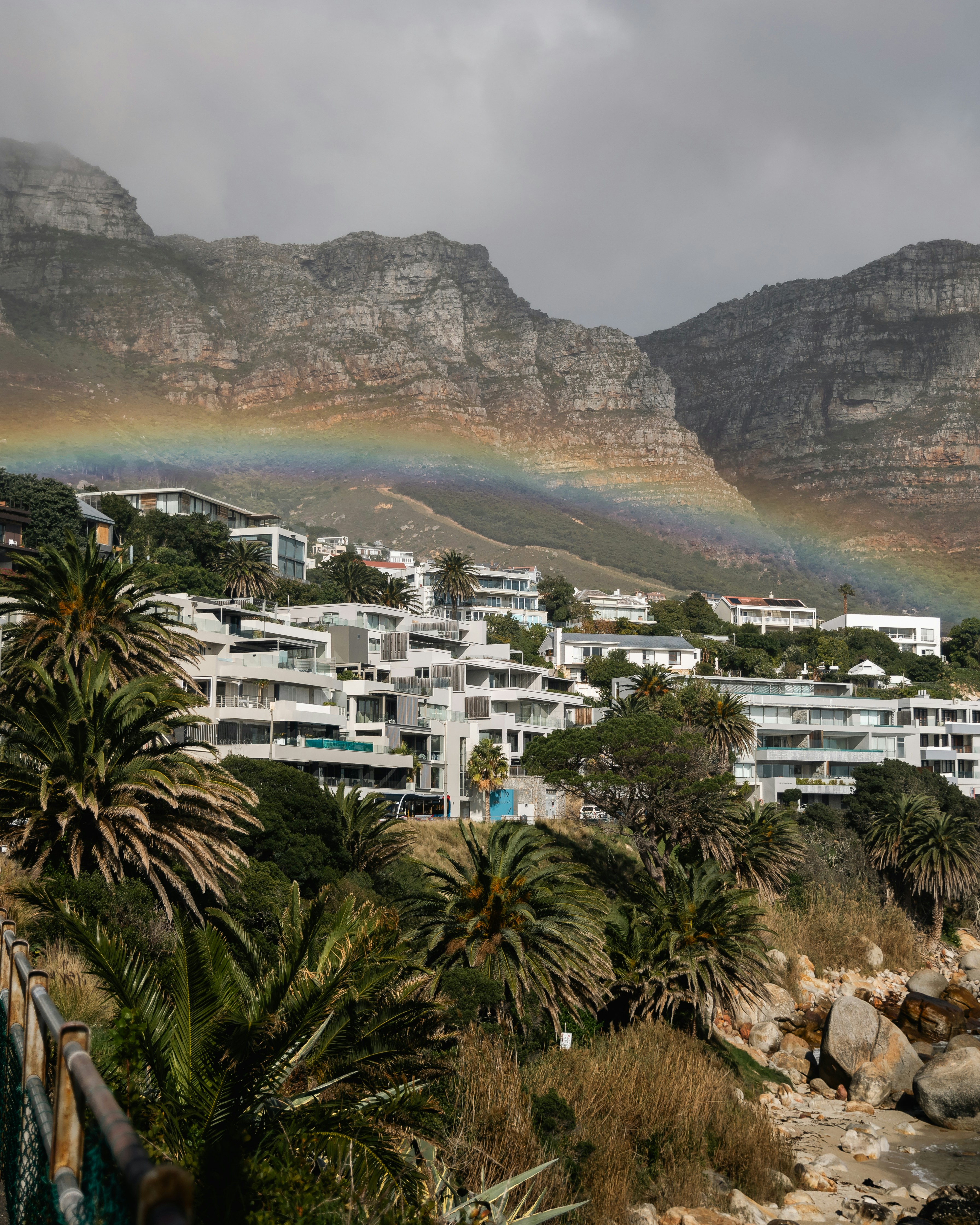 A magical moment - Rainbow over Camps Bay | Rainbow arcs over coastal homes and mountains.