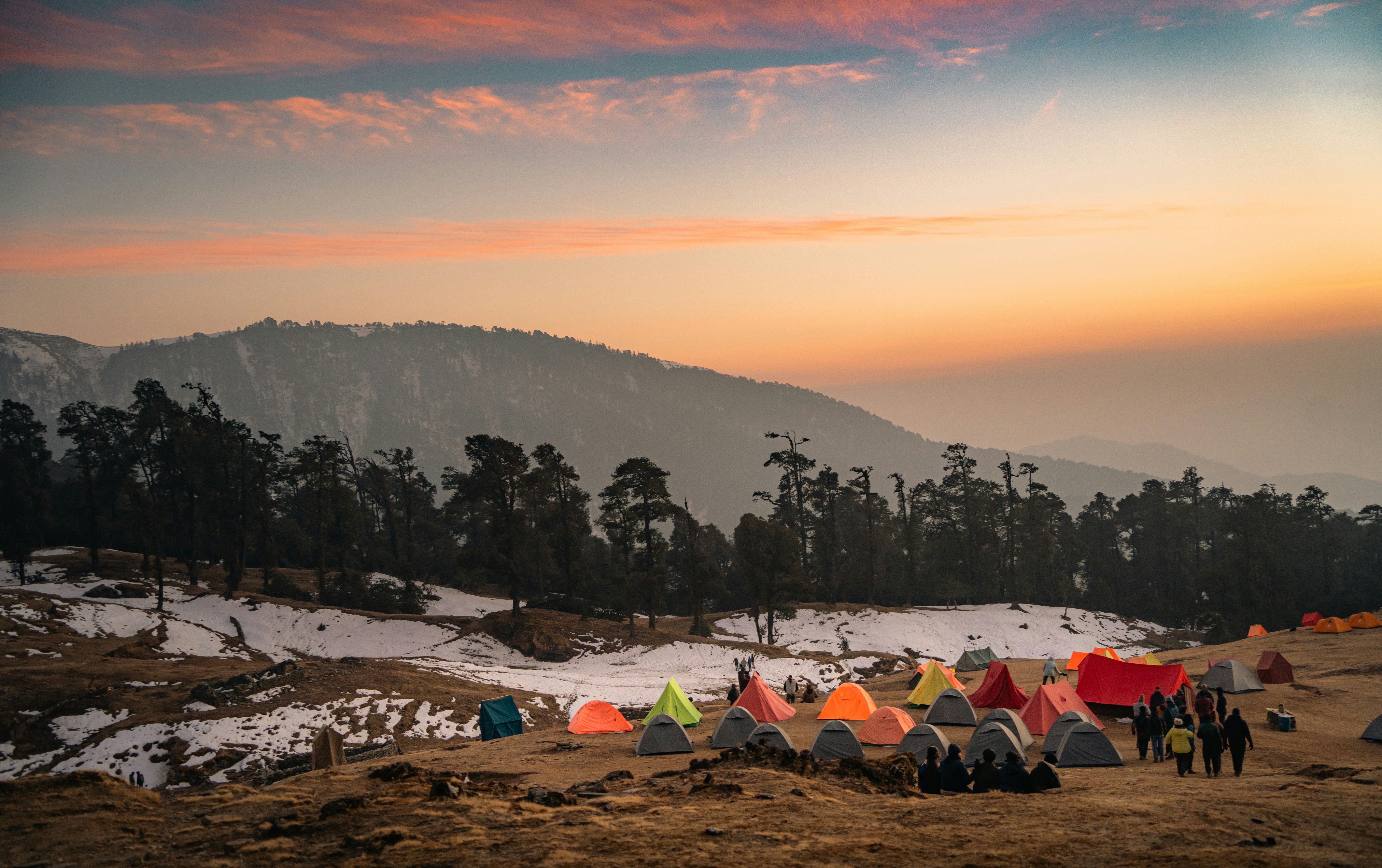 Camping tents sit below a beautiful sunset.