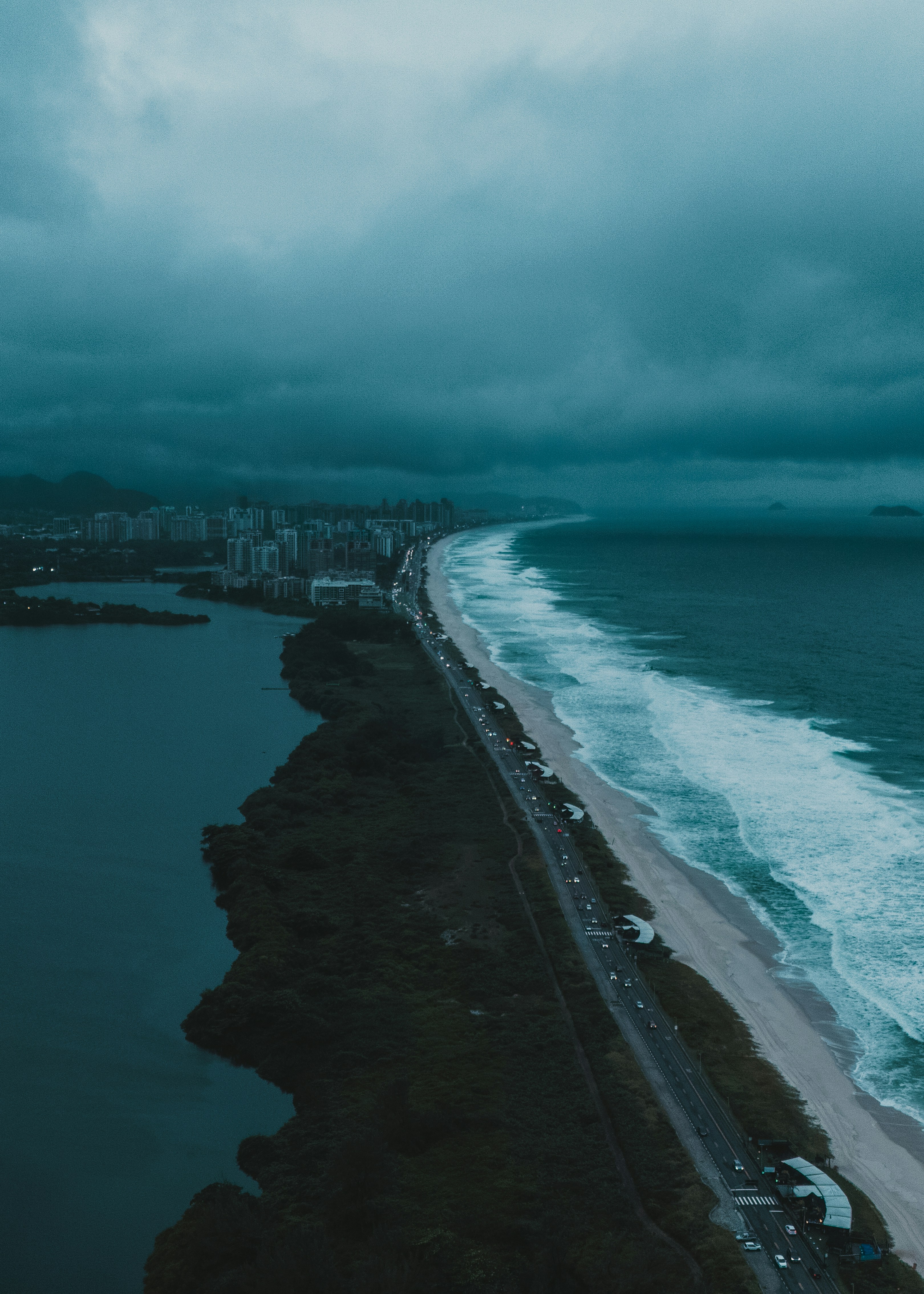 Road runs along the shore under a stormy sky.