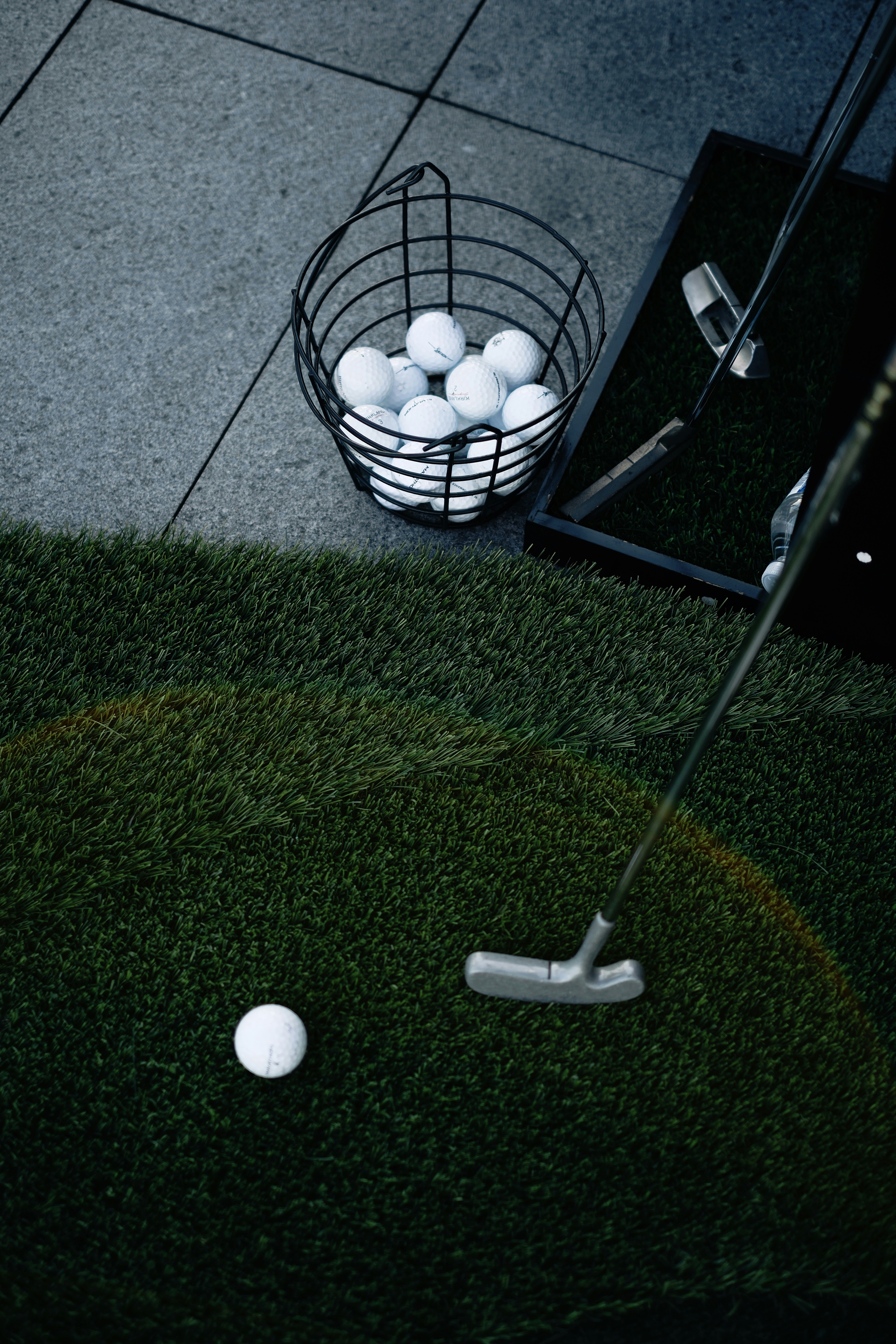 Basket of White Golf Balls Anchoring a Quiet Practice on the Turf Green