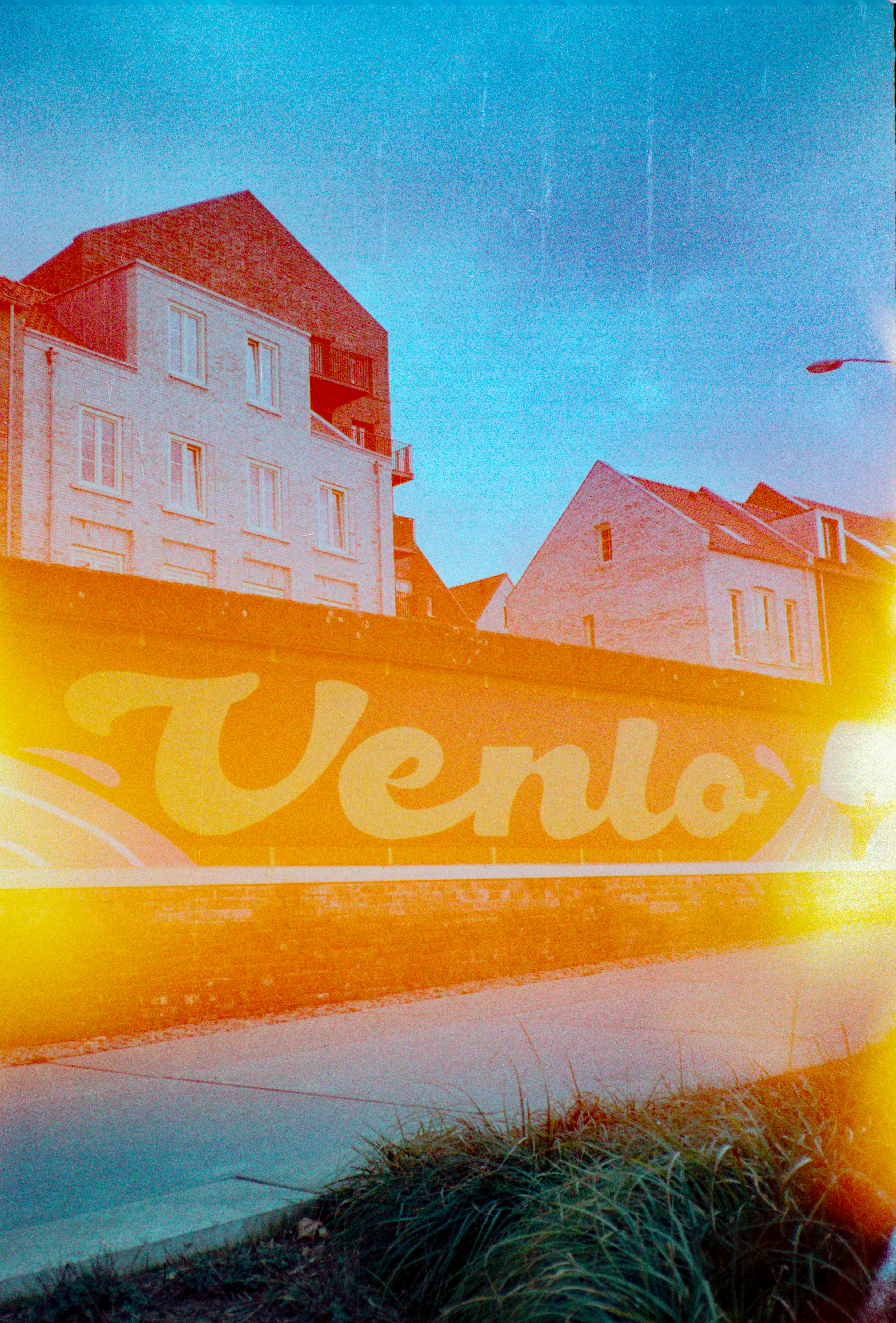 Vibrant mural reading 'Venlo' against a backdrop of urban architecture, capturing the essence of city life. The artwork blends seamlessly with the surrounding buildings.